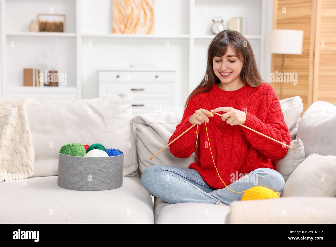Beautiful woman knitting on sofa at home Stock Photo - Alamy