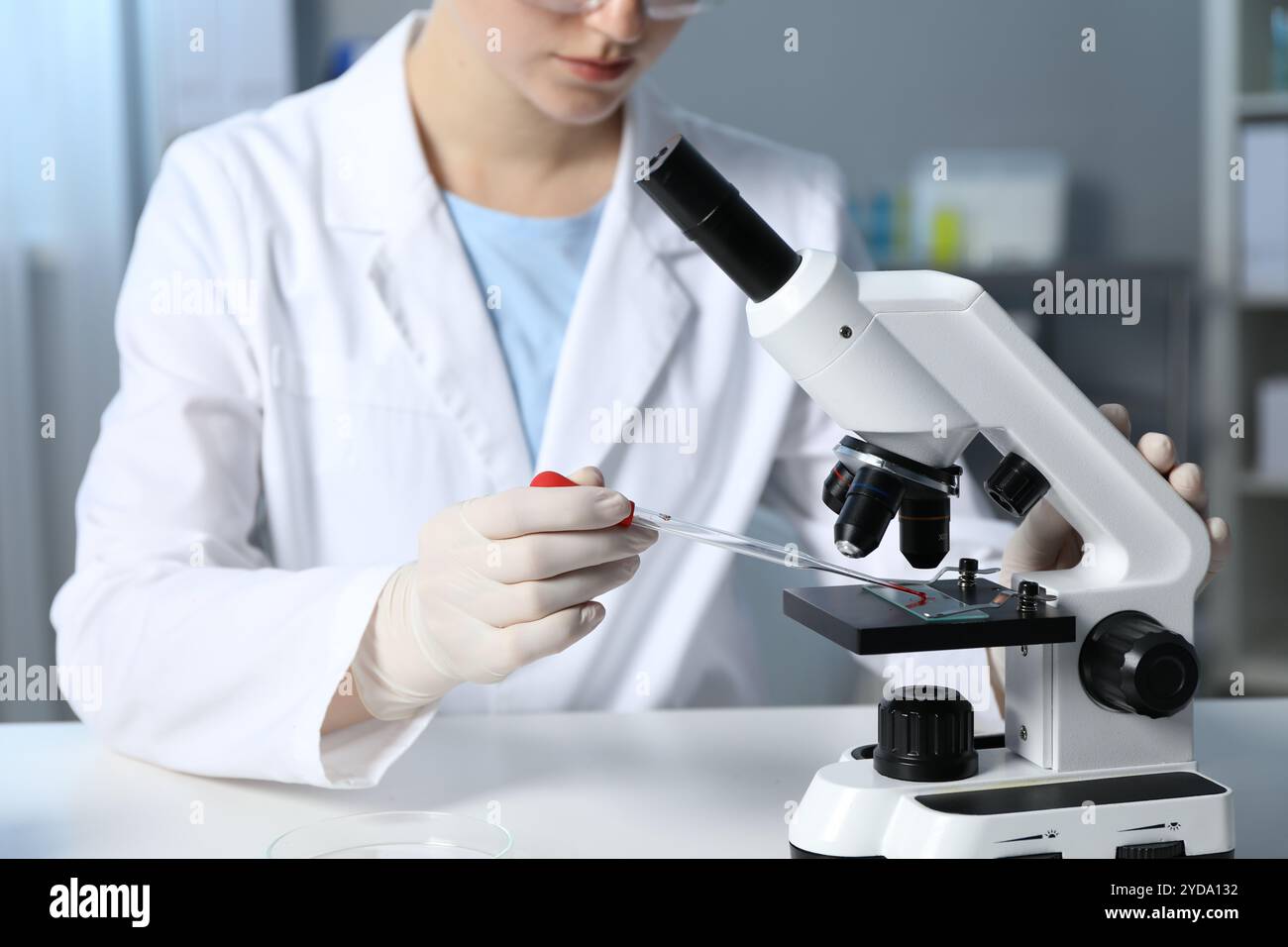 Laboratory testing. Doctor dripping blood sample onto glass slide while ...