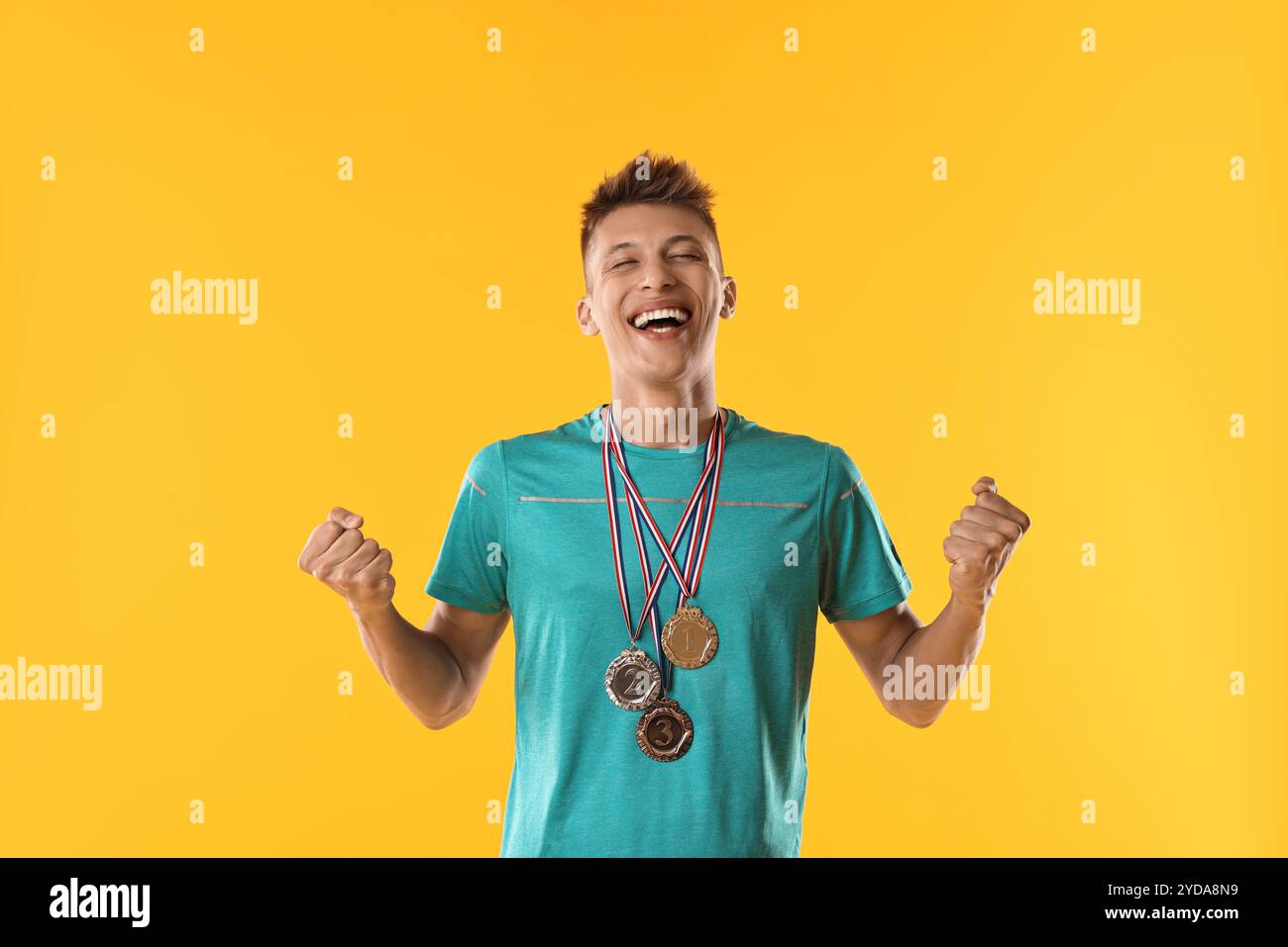 Happy winner with different medals on yellow background Stock Photo - Alamy