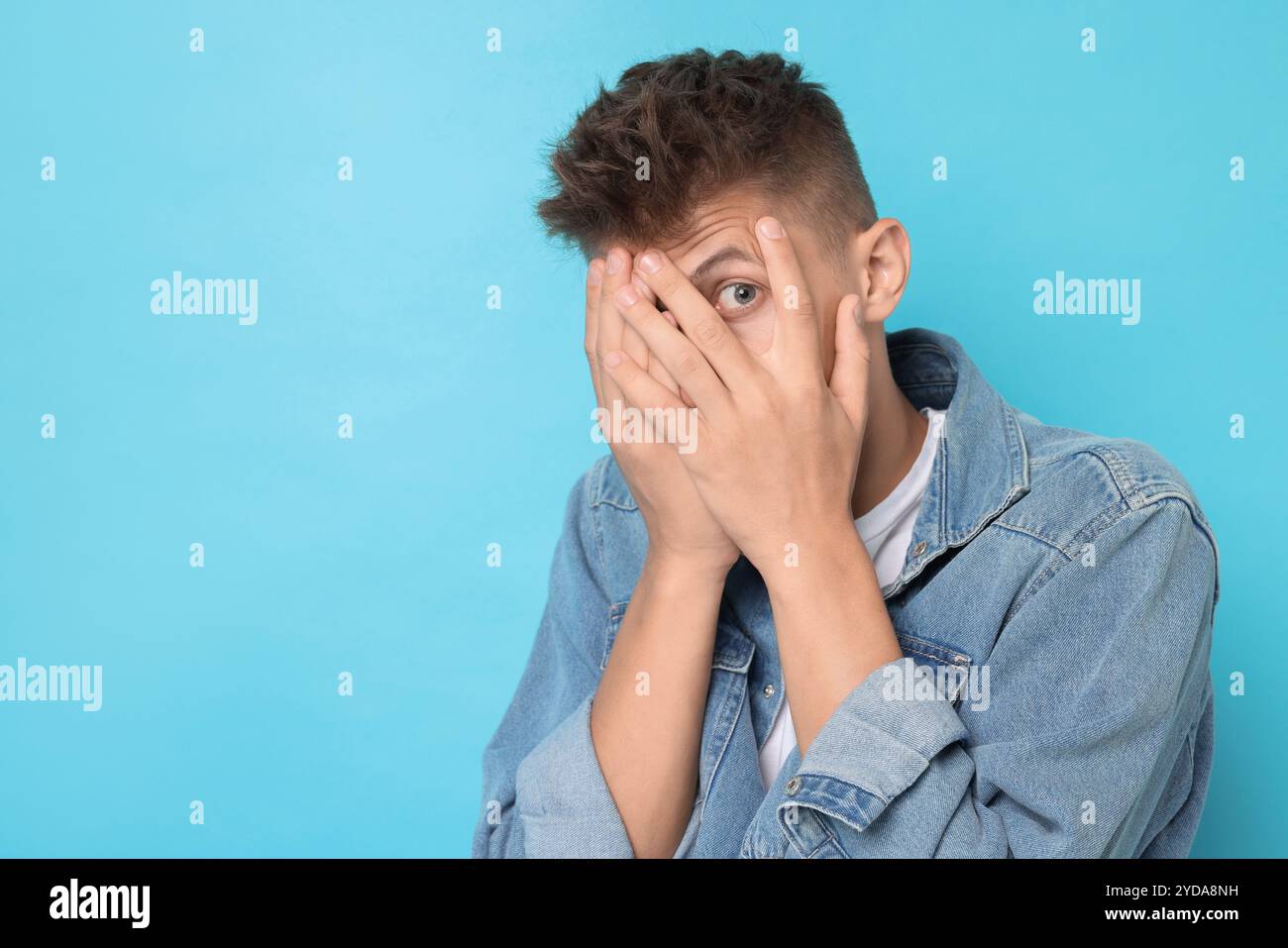 Portrait of scared young man on light blue background, space for text ...