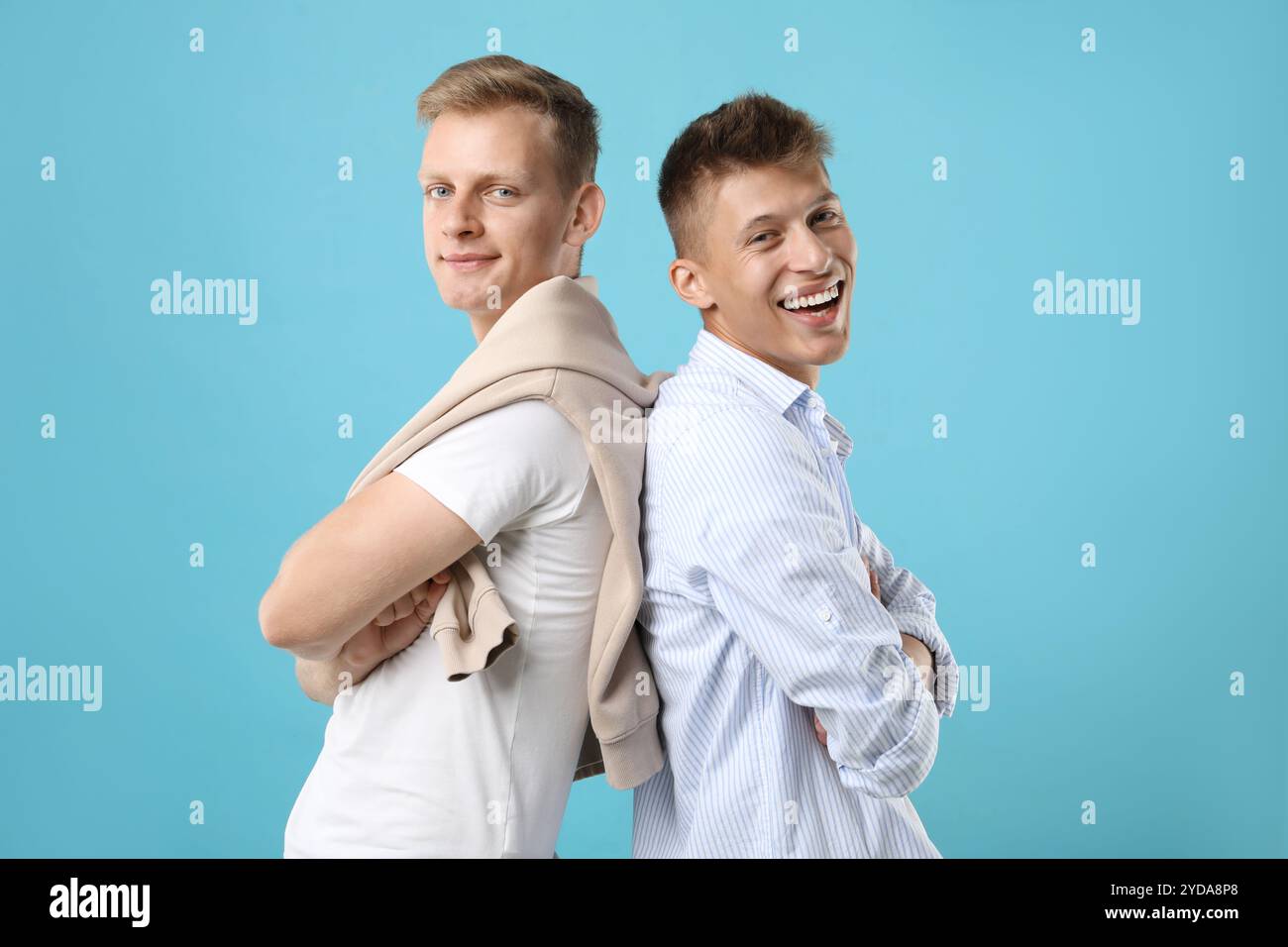 Happy brothers posing with crossed arms on light blue background Stock ...