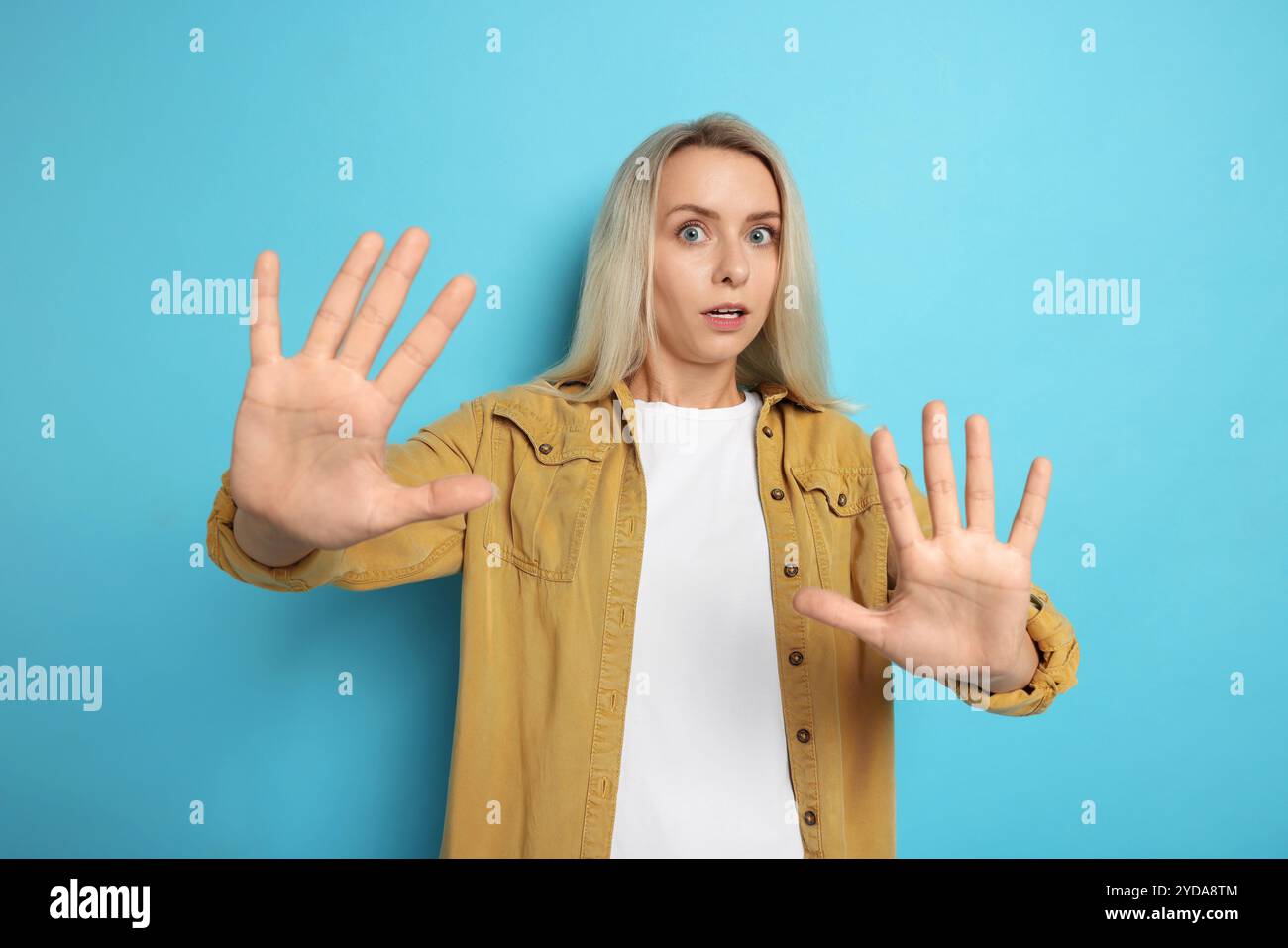 Portrait of scared woman on light blue background Stock Photo - Alamy