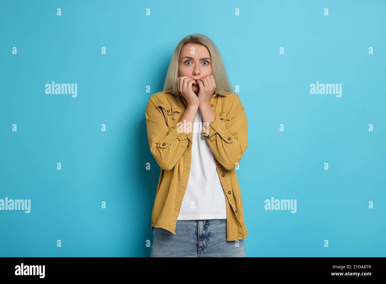Portrait of scared woman on light blue background Stock Photo - Alamy