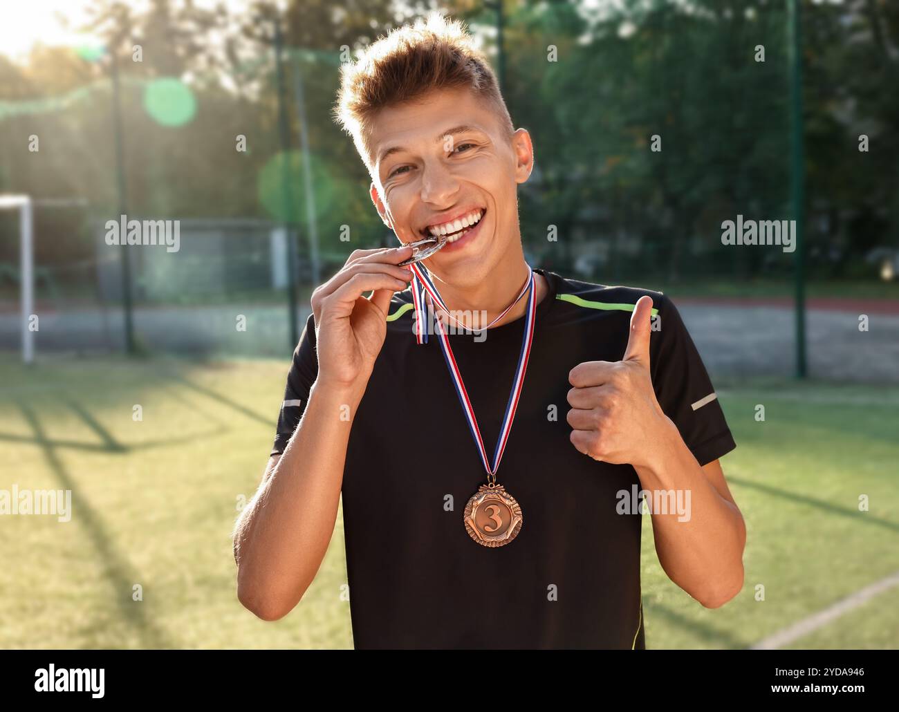 Happy winner with different medals showing thumbs up at stadium on ...