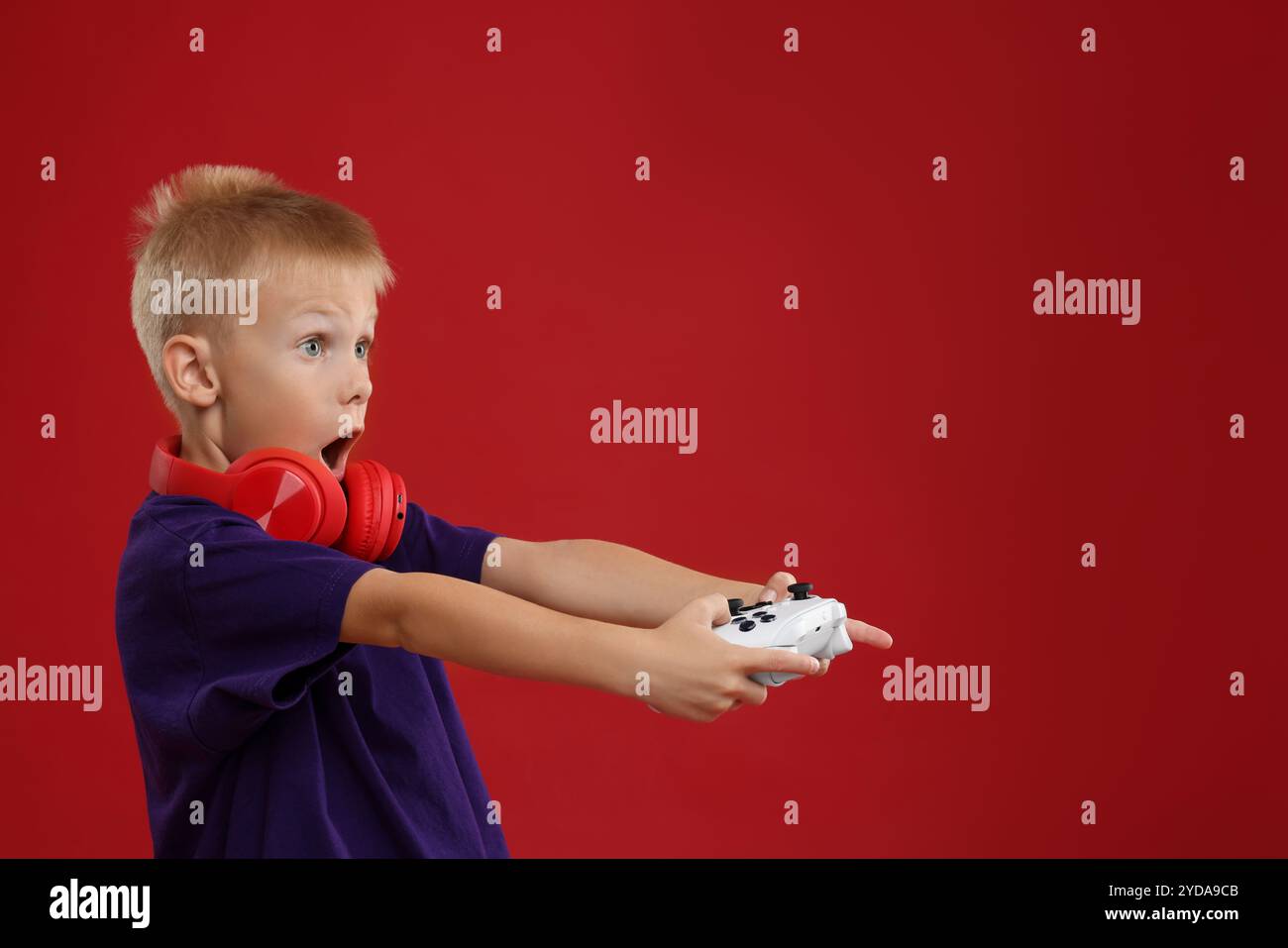 Cute little boy playing video game with controller on red background ...