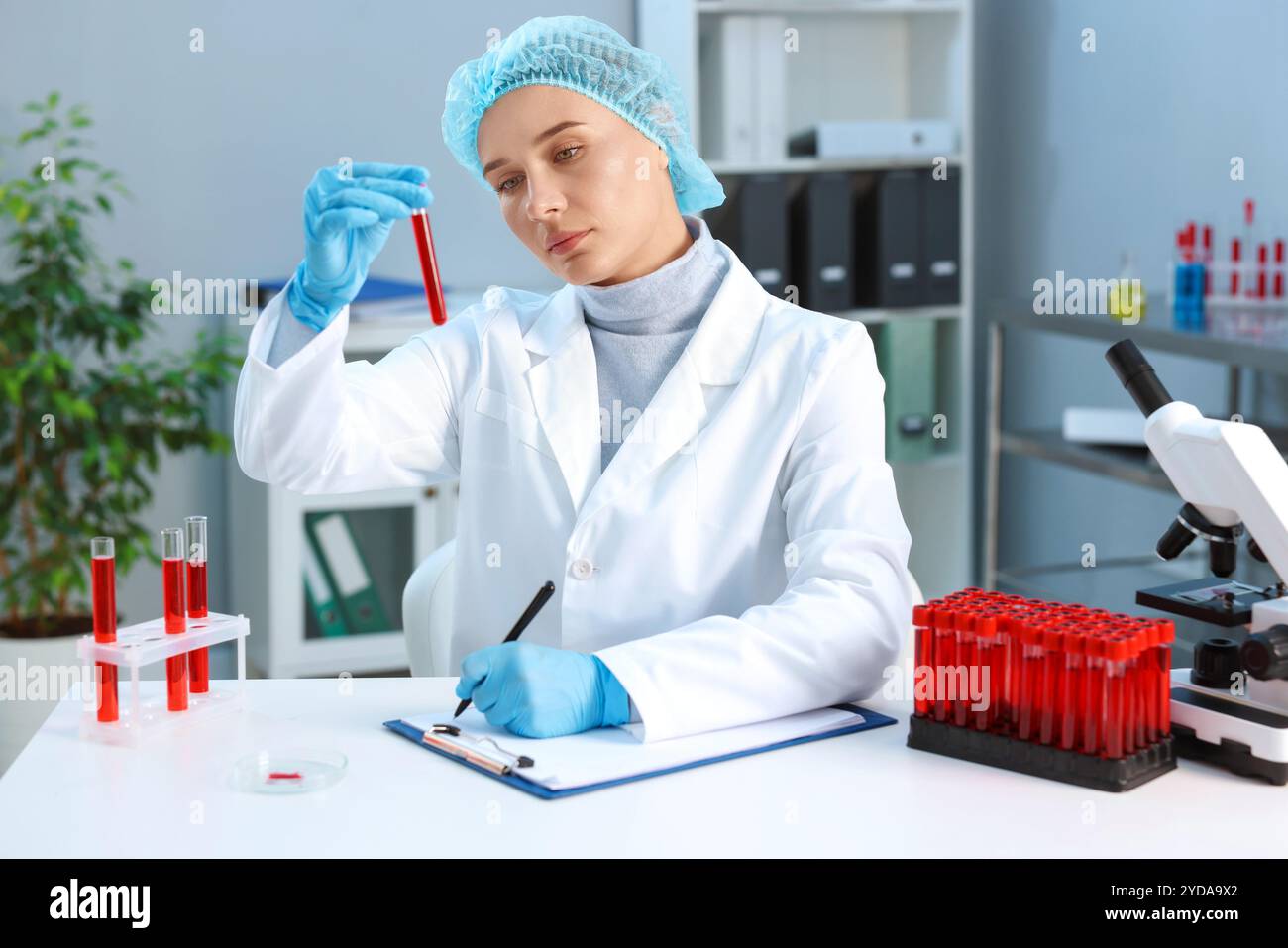 Laboratory testing. Doctor with blood sample taking notes at table ...
