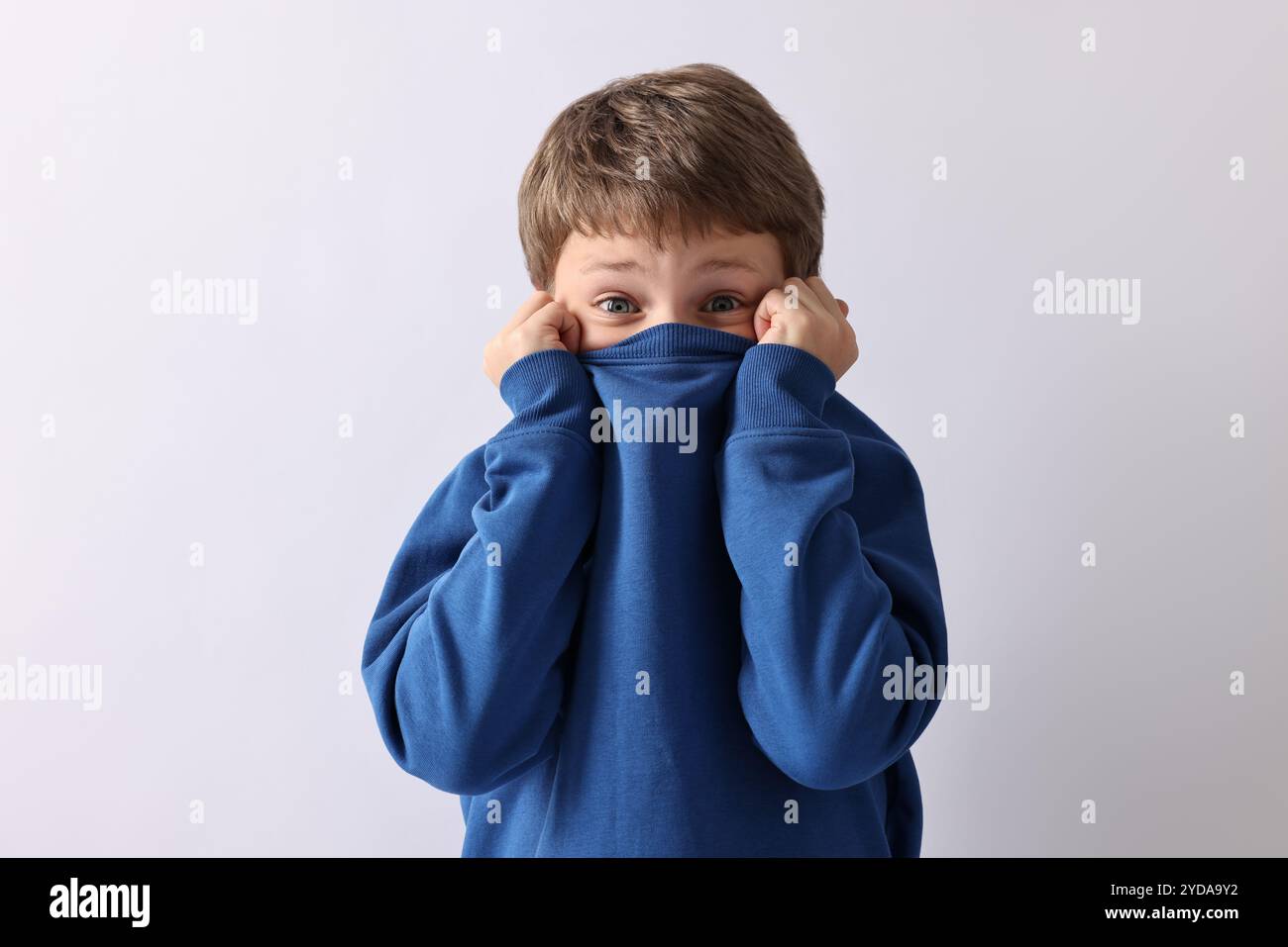 Scared little boy hiding on light background Stock Photo - Alamy