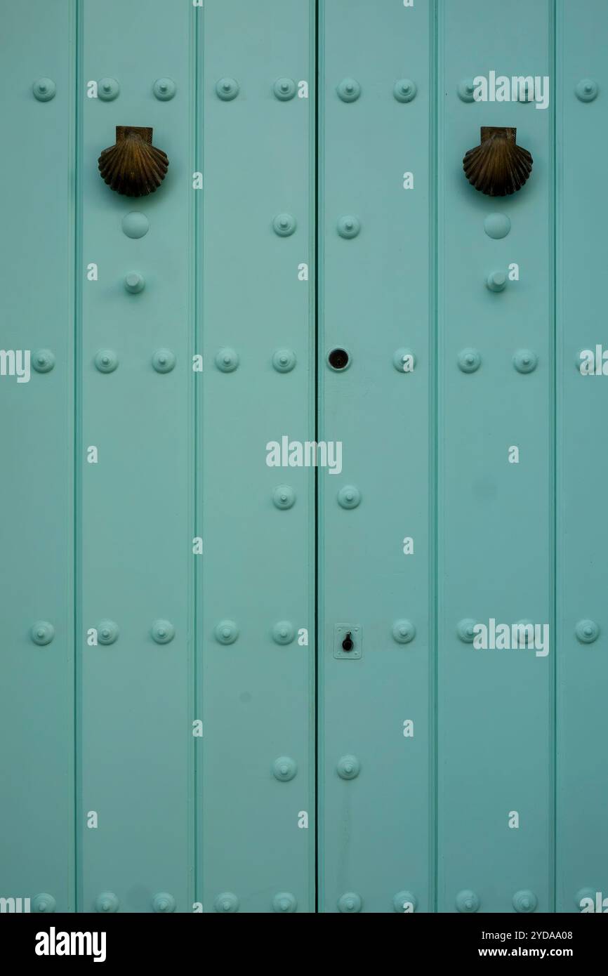 Green wooden door decorated with nails and bronze knockers shaped like ...