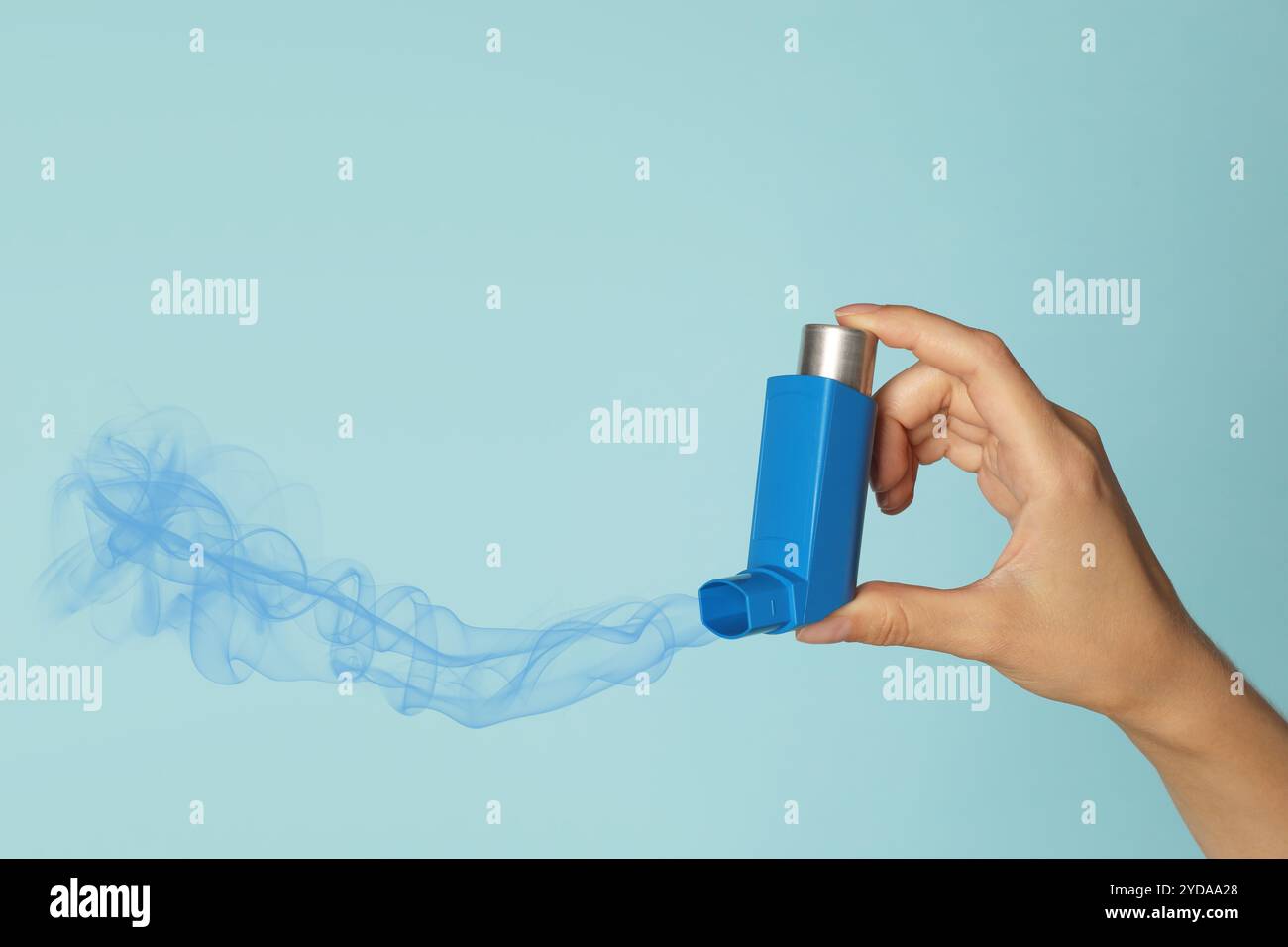 Asthma treatment. Woman holding inhaler on light blue background ...