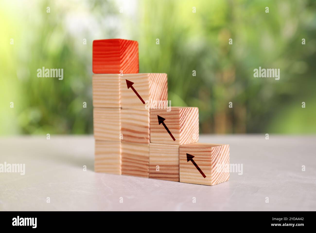 Stair made of wooden blocks on table. Cubes with arrows showing way to ...