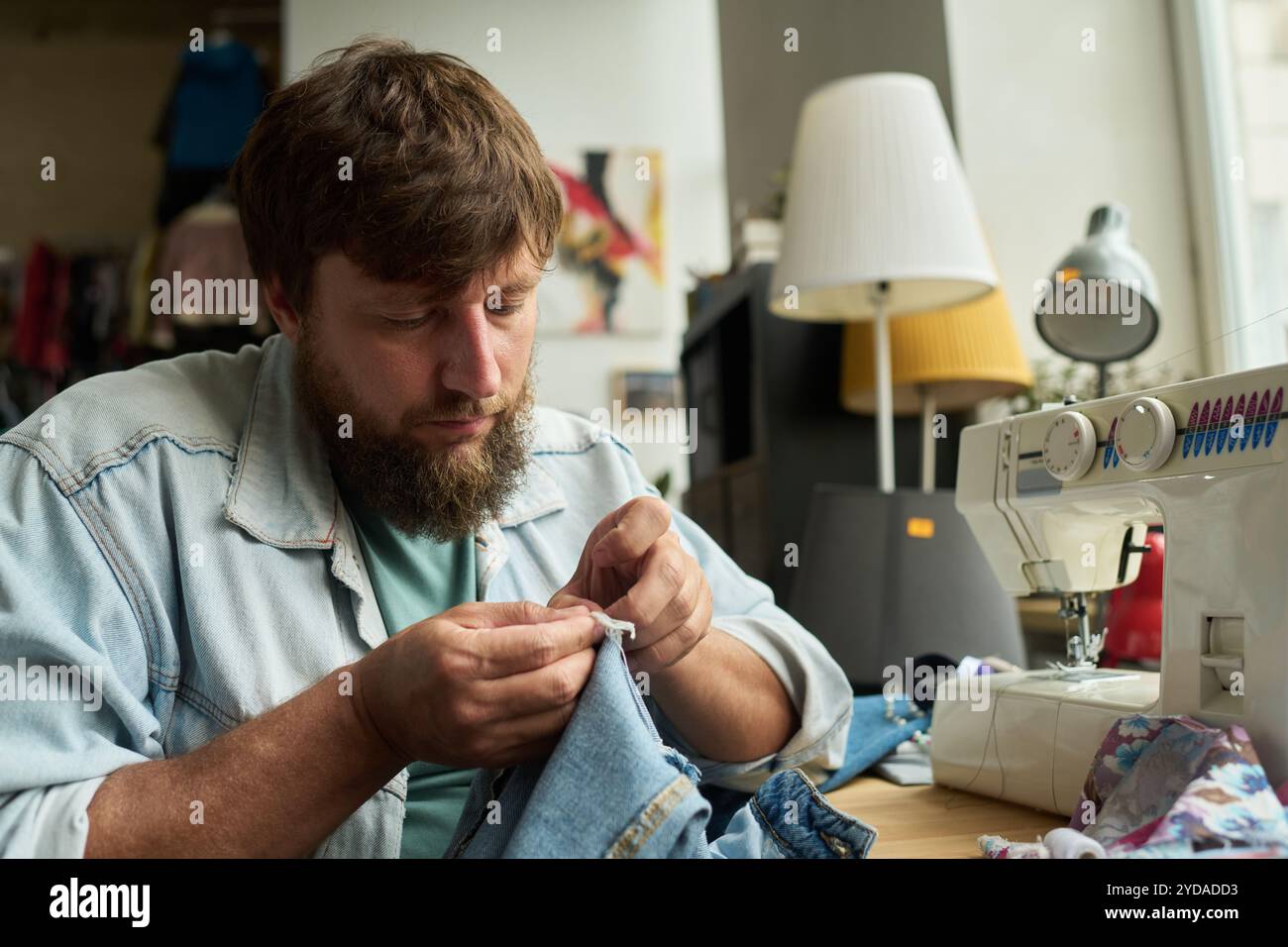 Young male worker of thrift shop sitting in front of camera and ripping ...