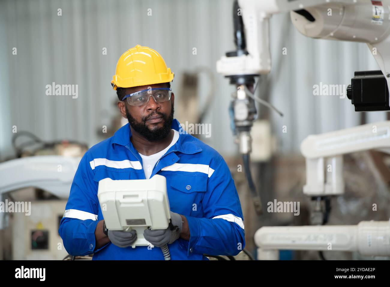 Young male engineers are manipulating a welding robot hand. By ...