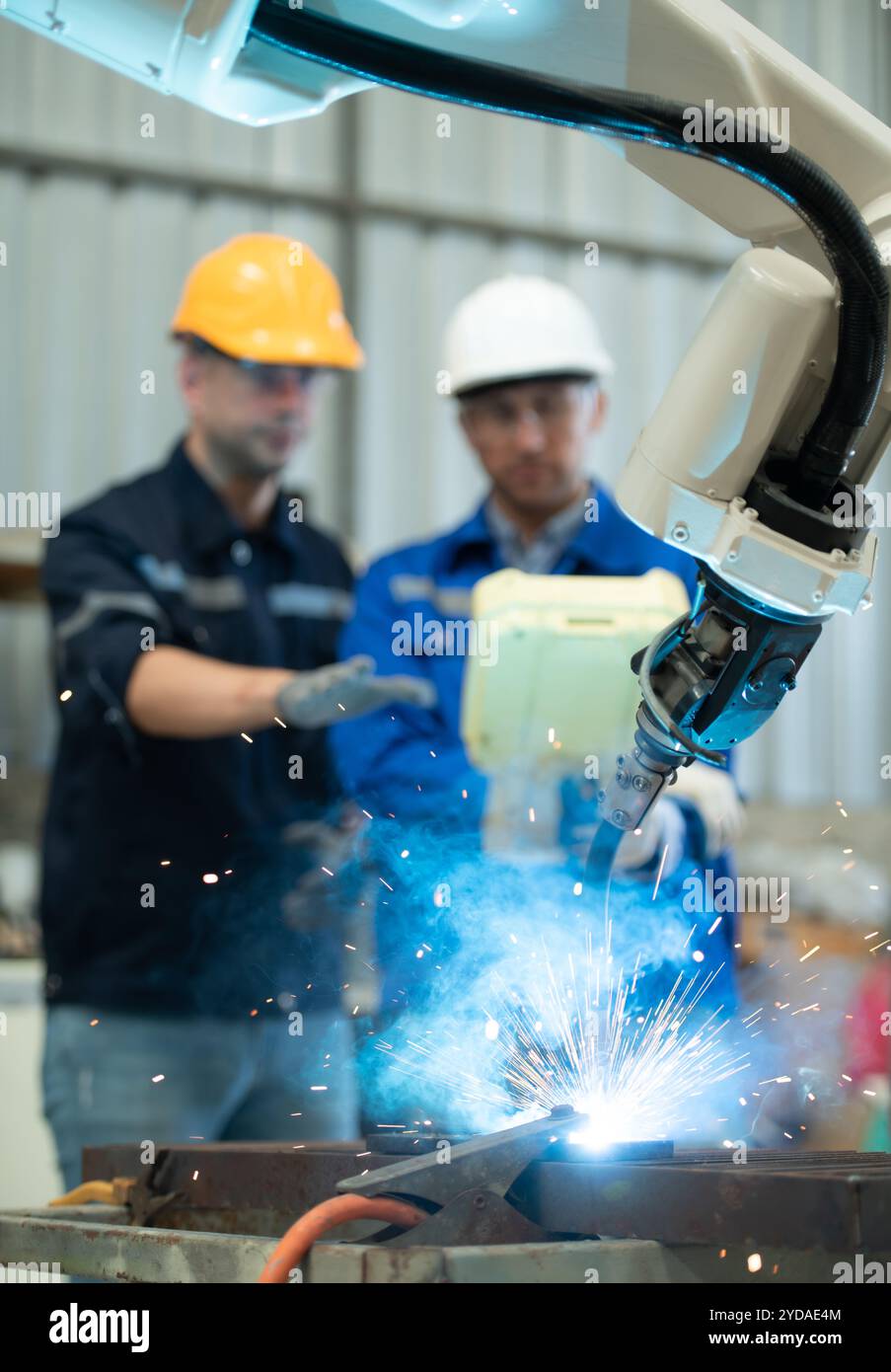 Both of engineers are manipulating a welding robot hand. By combining ...