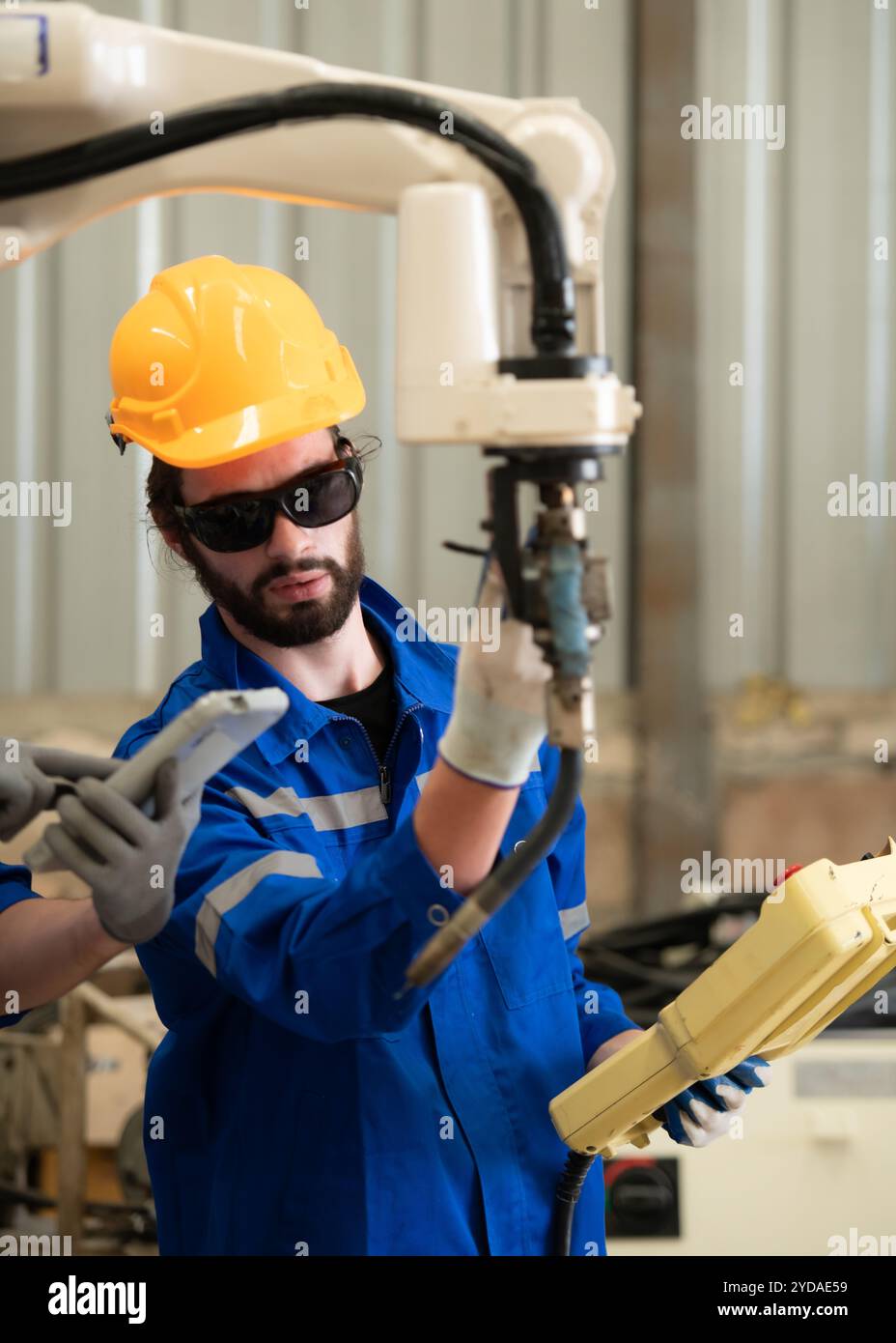 Young male engineers are manipulating a welding robot hand. By ...