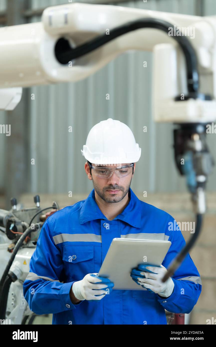 Young male engineers are manipulating a welding robot hand. By ...
