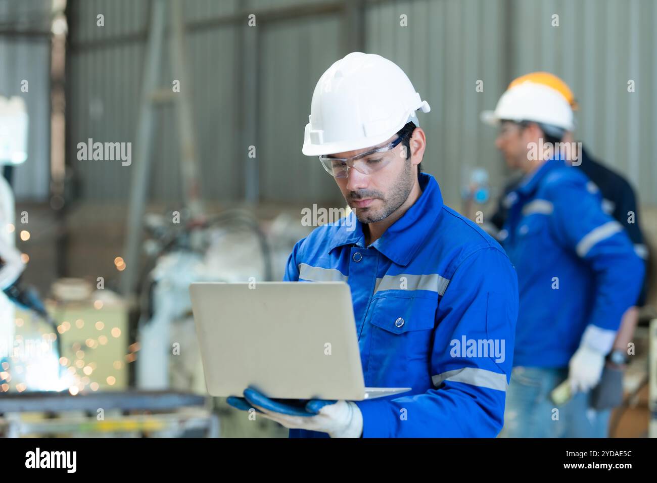Group of engineers are manipulating a welding robot hand. By combining ...