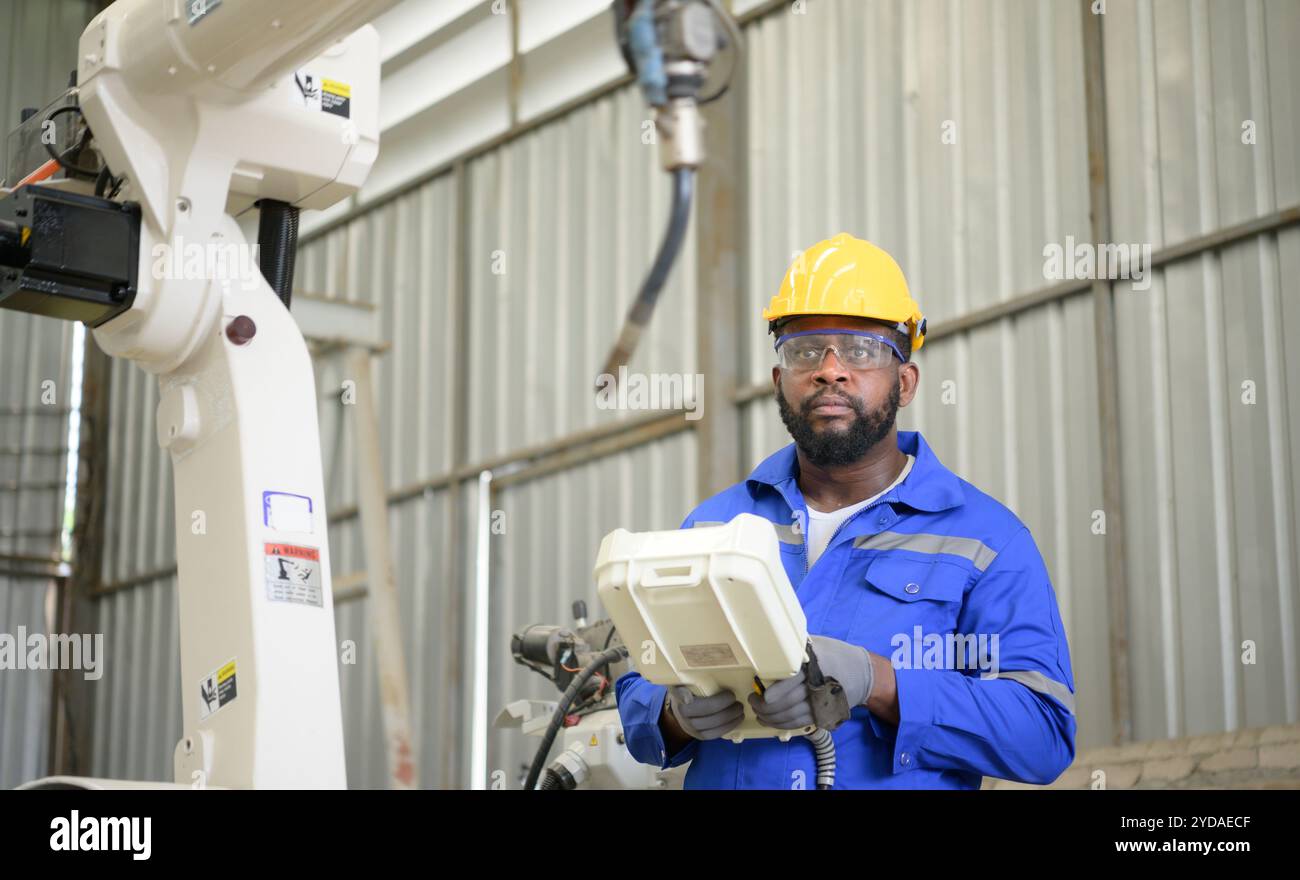 Young male engineers are manipulating a welding robot hand. By ...