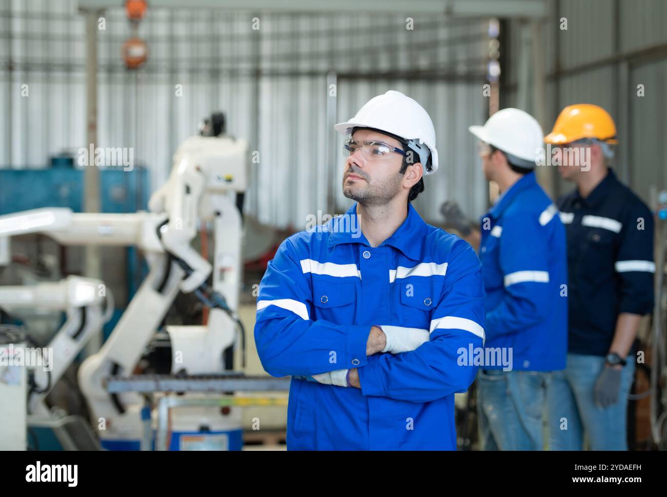 Group of engineers are manipulating a welding robot hand. By combining ...