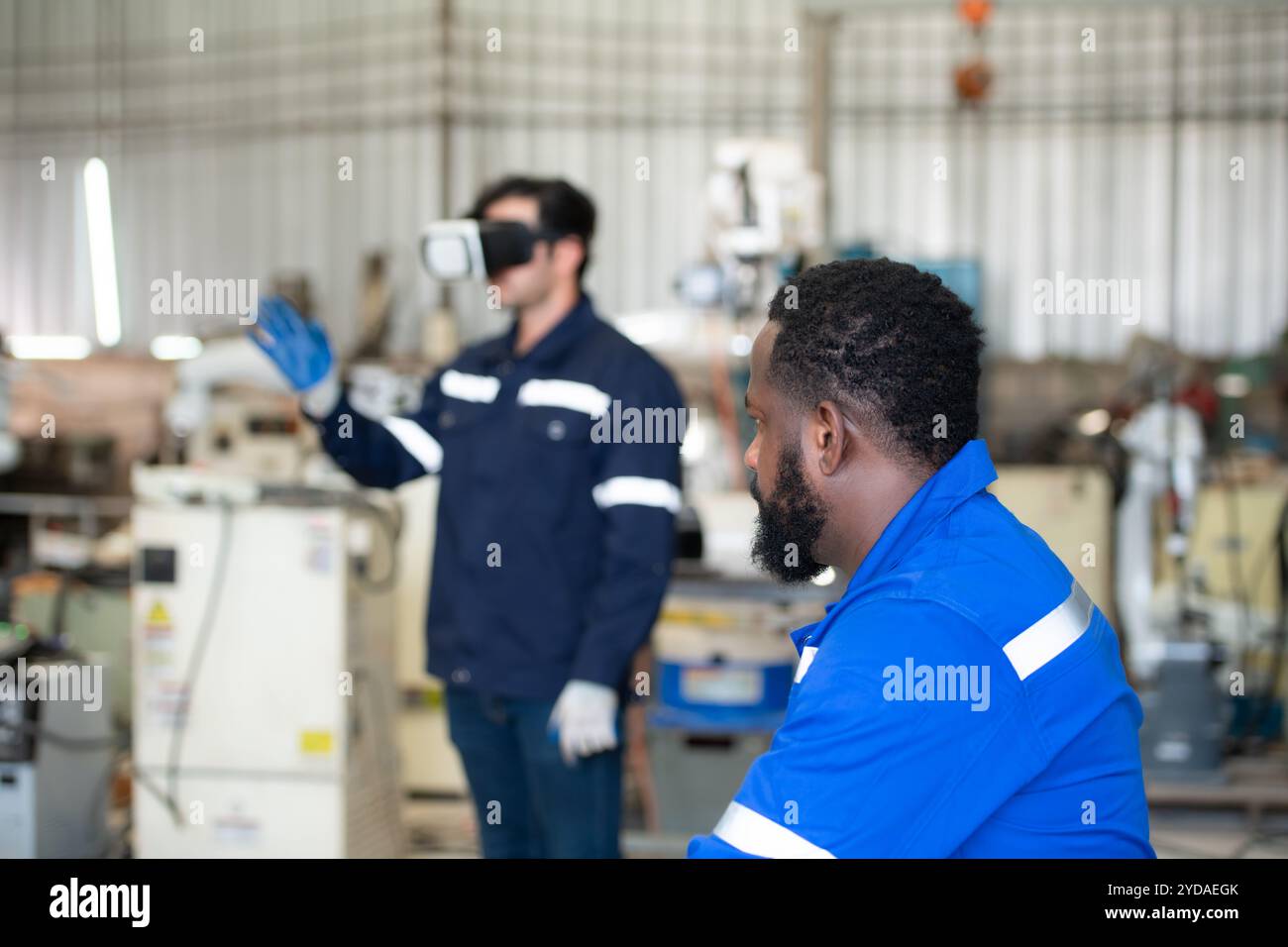 Chief and young male engineer uses a VR machine to operate a welding ...