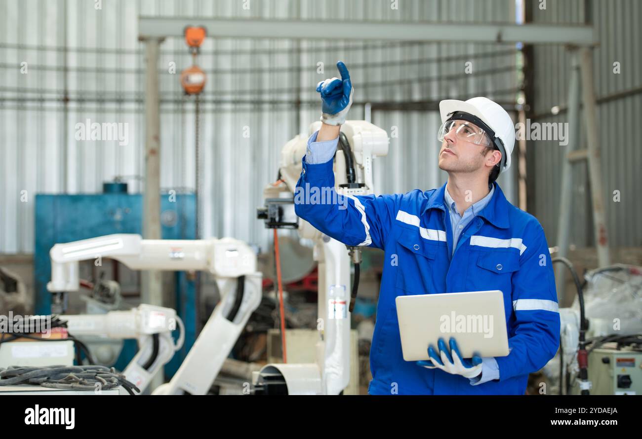 Young male engineers are manipulating a welding robot hand. By ...