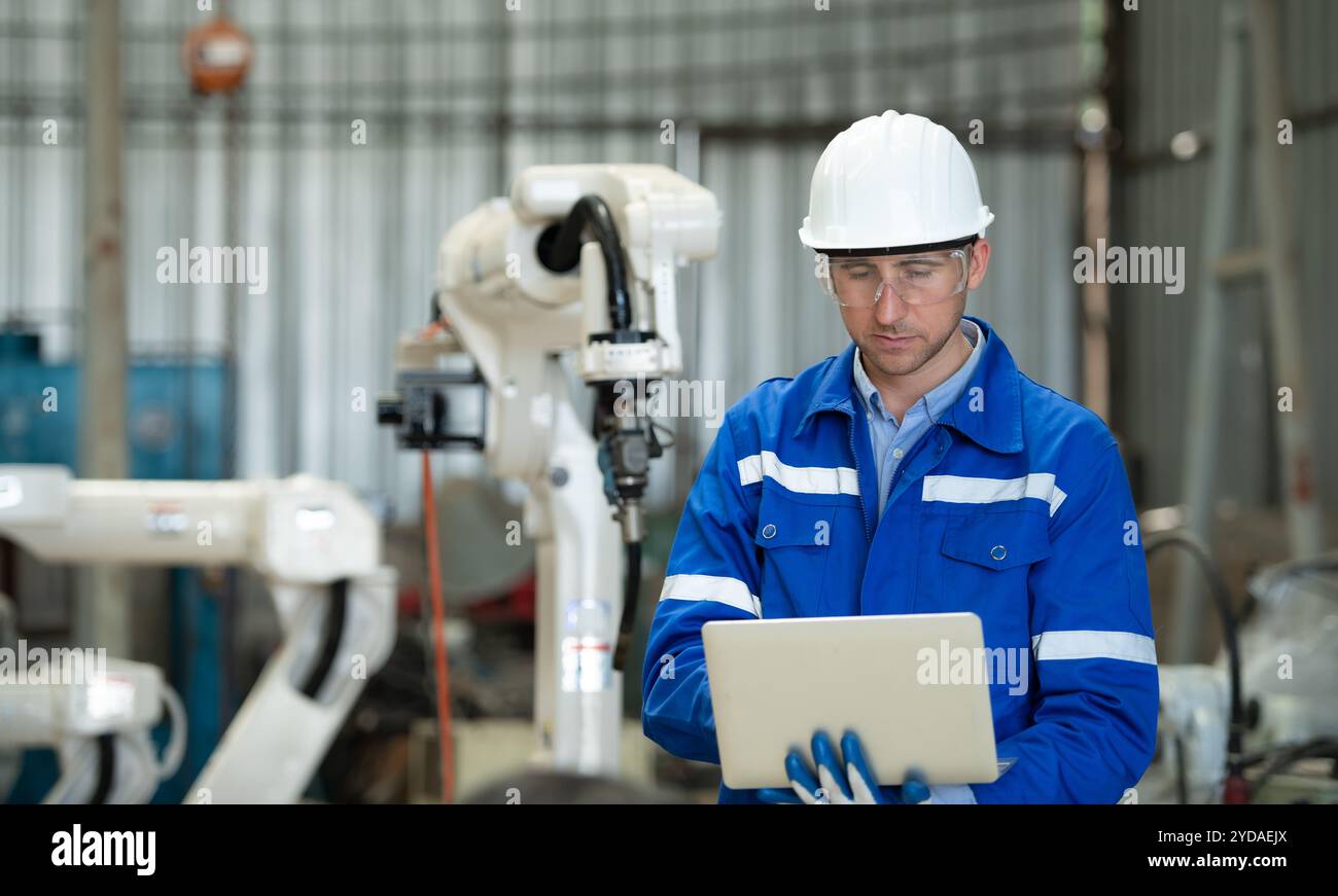 Young male engineers are manipulating a welding robot hand. By ...