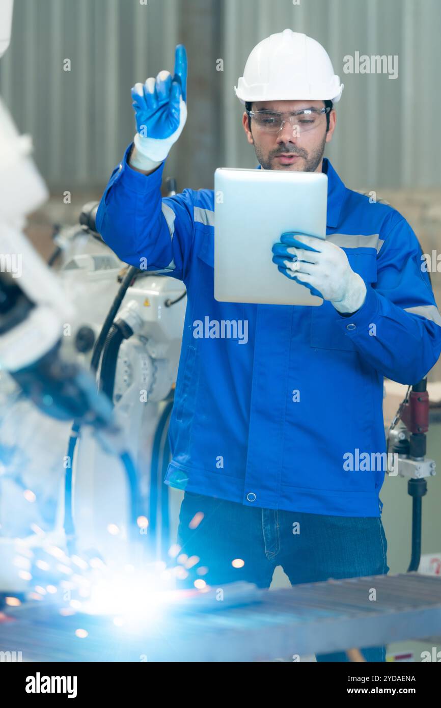 Young male engineers are manipulating a welding robot hand. By ...