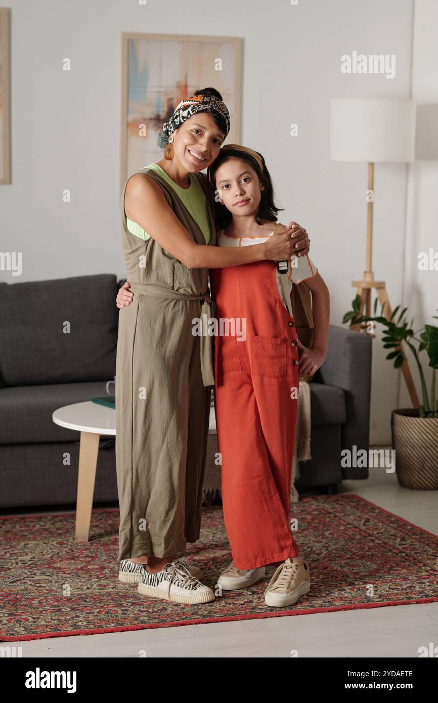 Mother and daughter embracing in bright living room with colorful decor ...