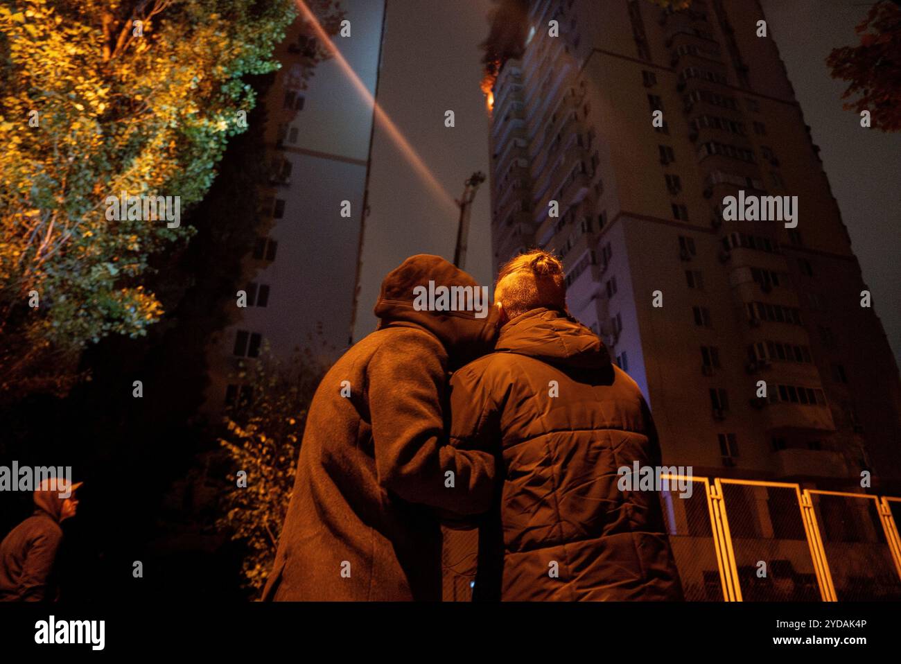 A couple comforts each other while watching a fire in a residential building after Russian ...