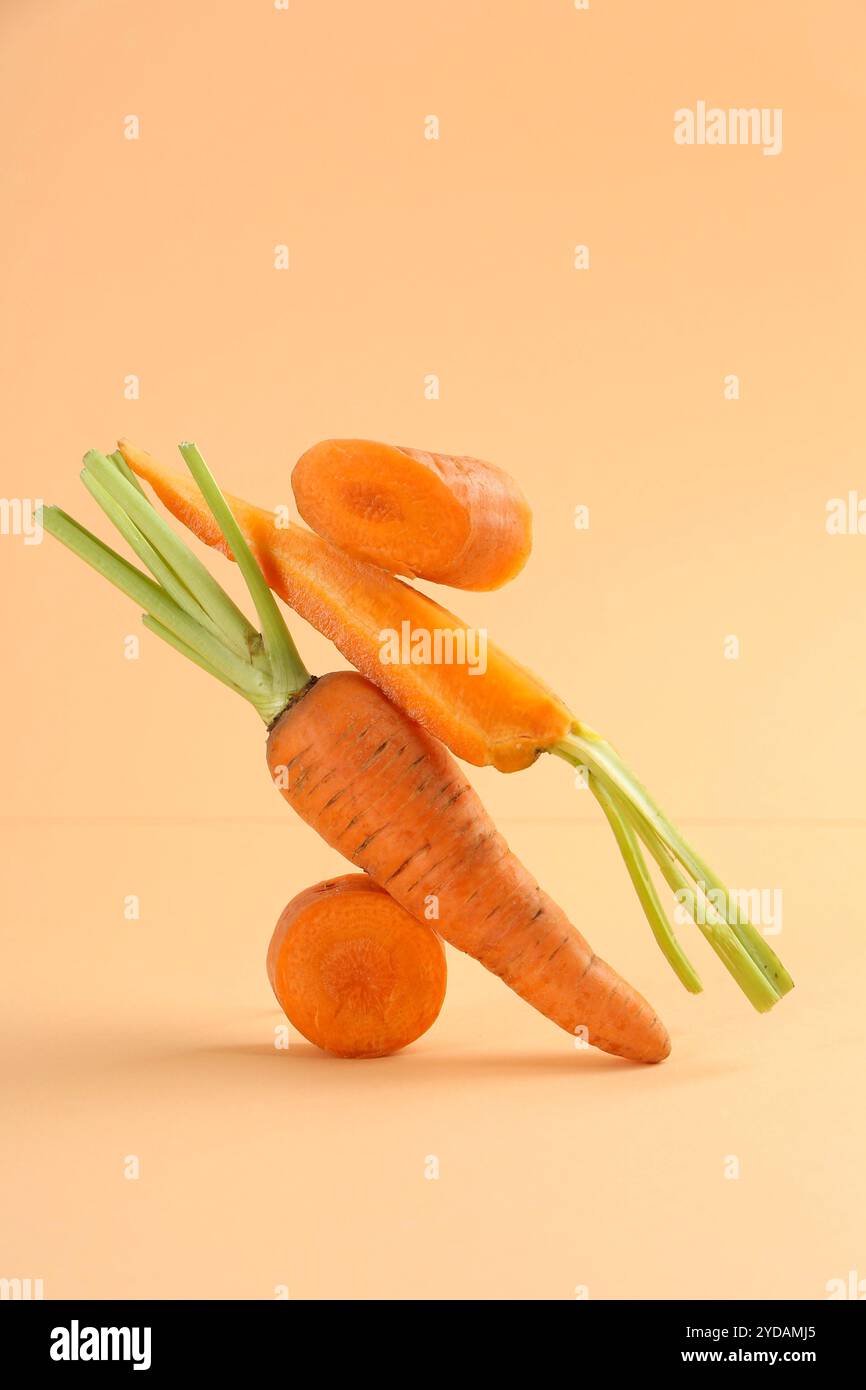 Whole and cut fresh carrots on pale orange background Stock Photo - Alamy