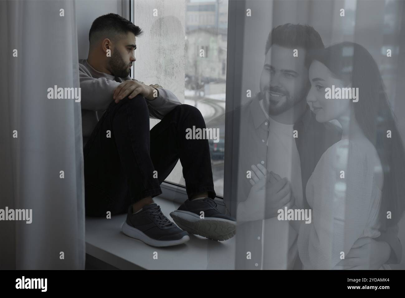 Loneliness. Sad man sitting near window in room and happy couple ...