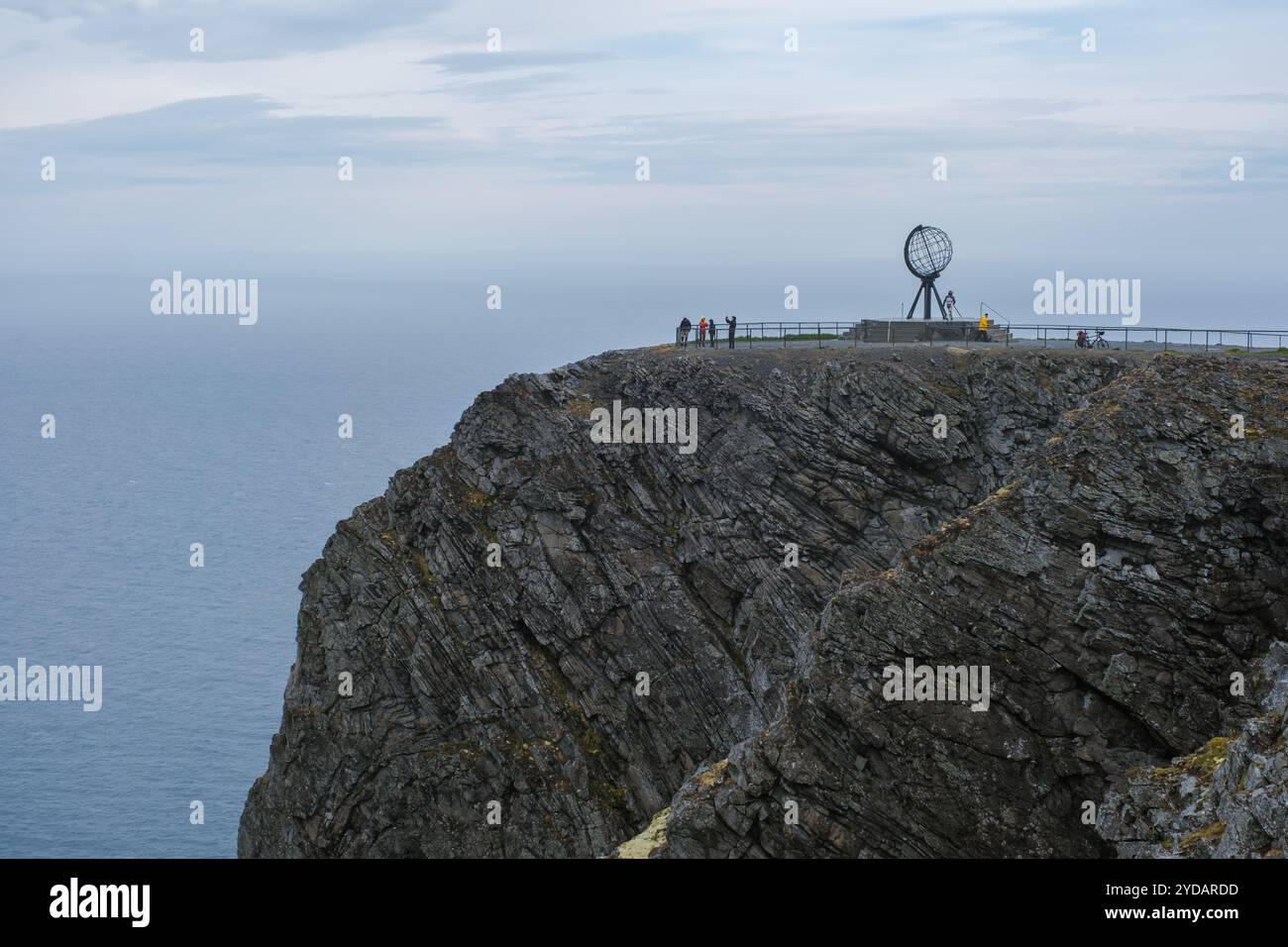 A group of tourists stand on the edge of a cliff, admiring the iconic ...