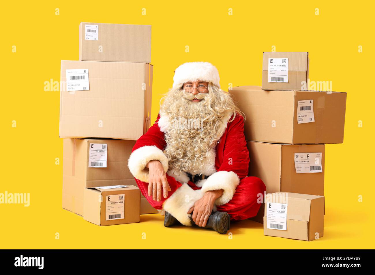 Santa Claus sitting on floor with parcels against yellow background ...
