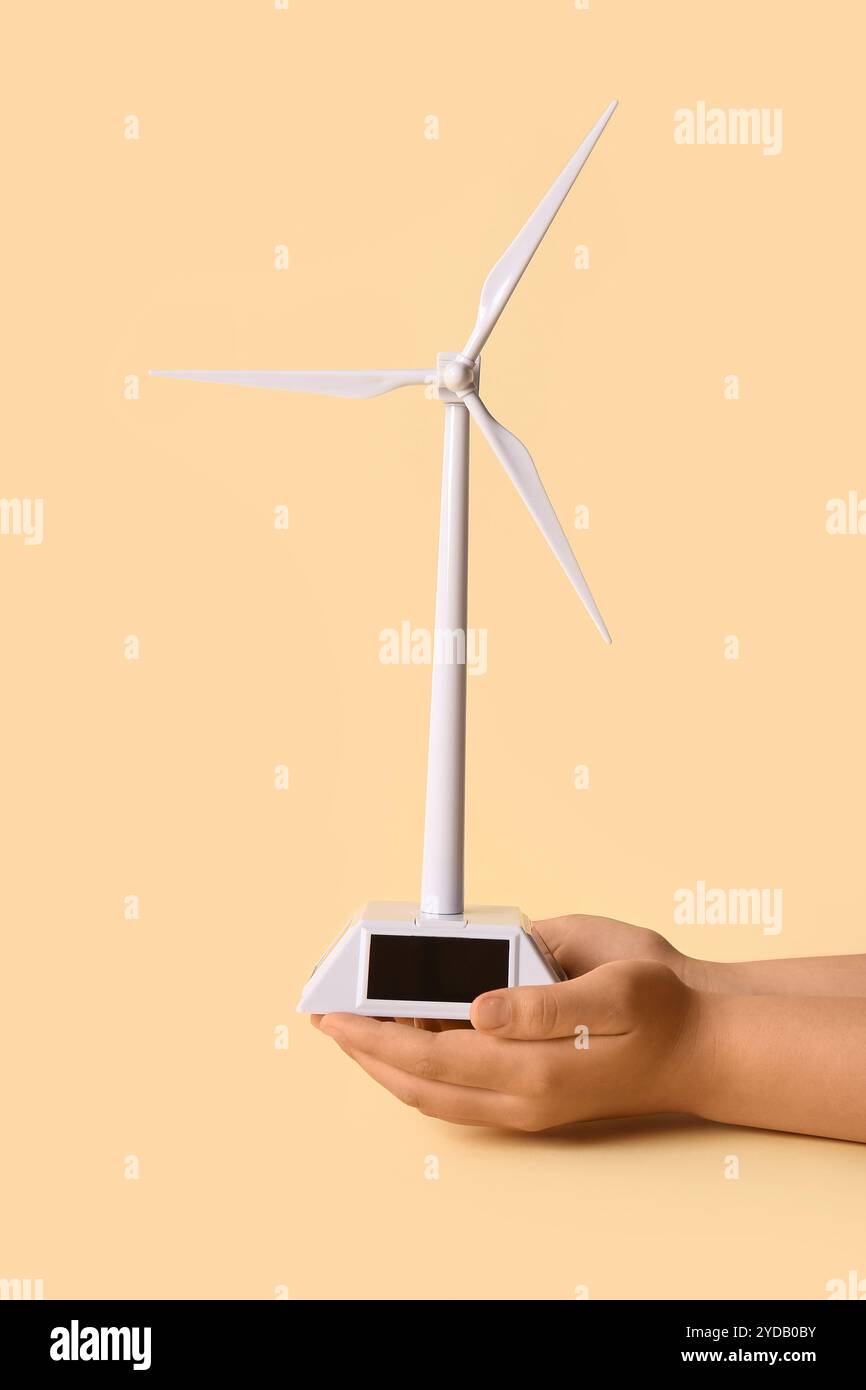 Female hands holding wind turbine model on beige background Stock Photo ...