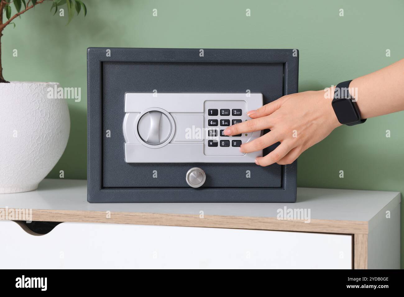 Woman opening safe on commode near green wall, closeup Stock Photo - Alamy