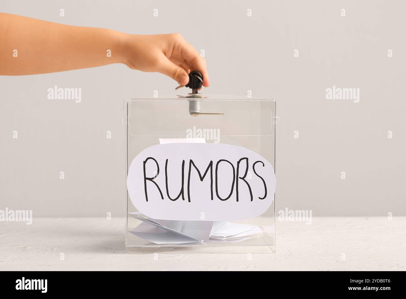 Woman opening box with word RUMORS on table against light background ...
