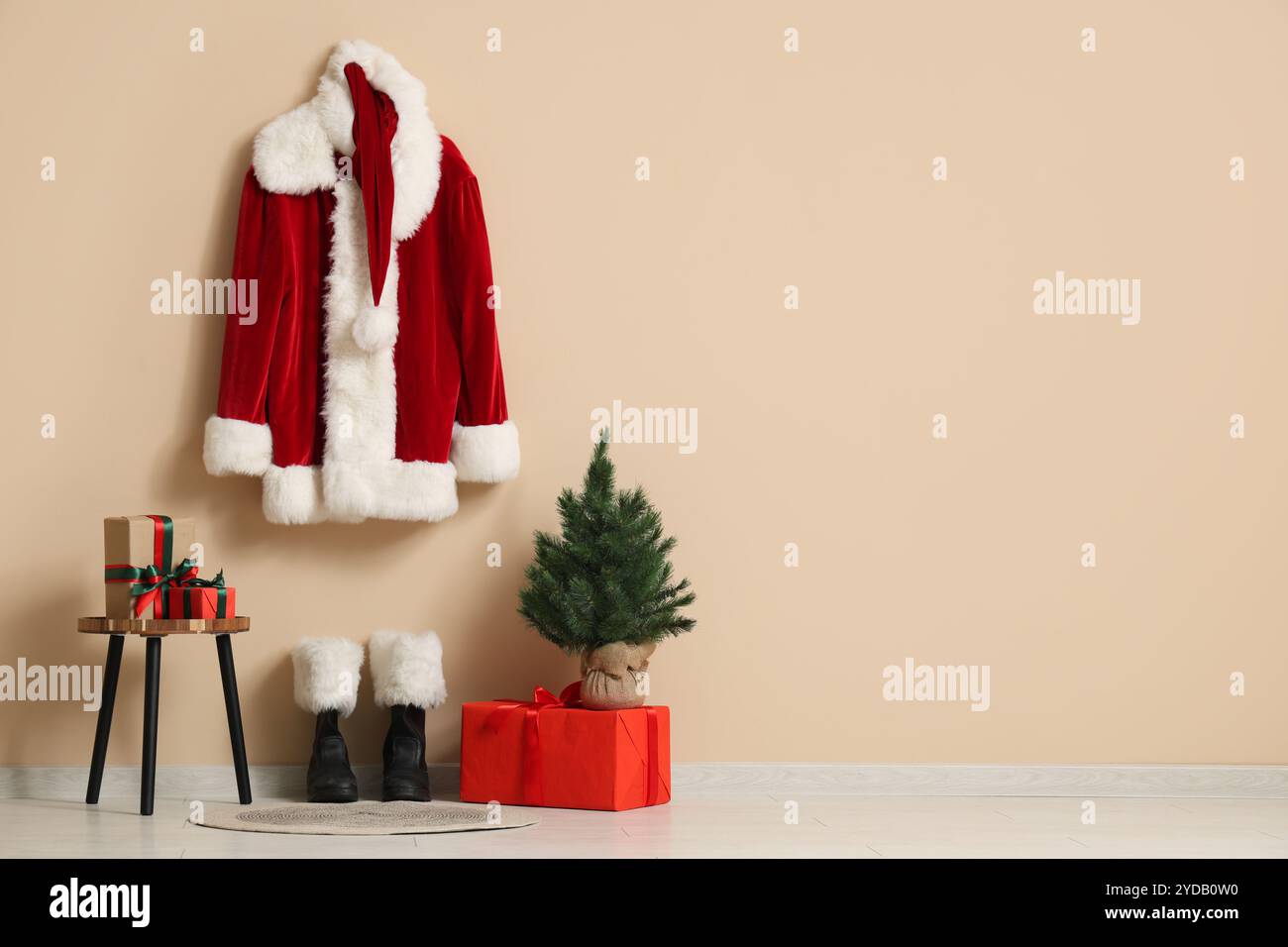 Santa Claus suit on hanger with gift boxes, fir tree and boots near ...