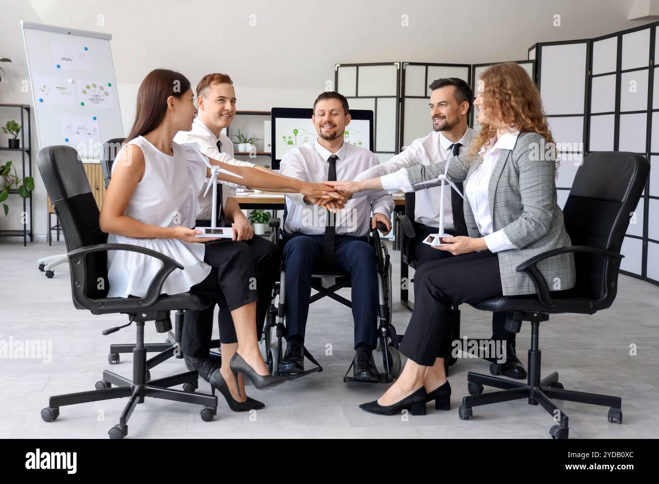 Business colleagues with wind turbine models putting hands together in ...