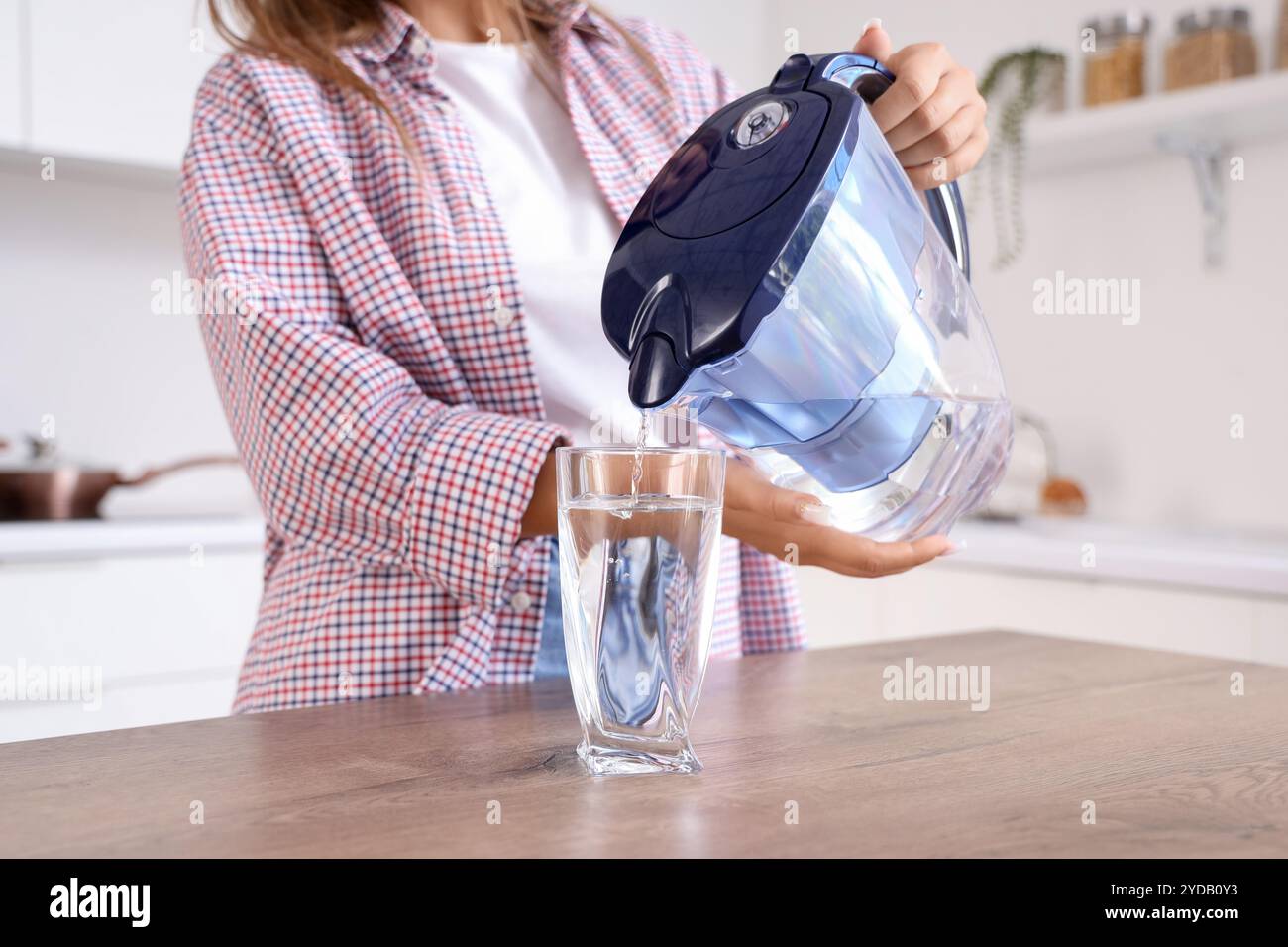 Young woman pouring water from filter pitcher into glass in kitchen Stock Photo - Alamy