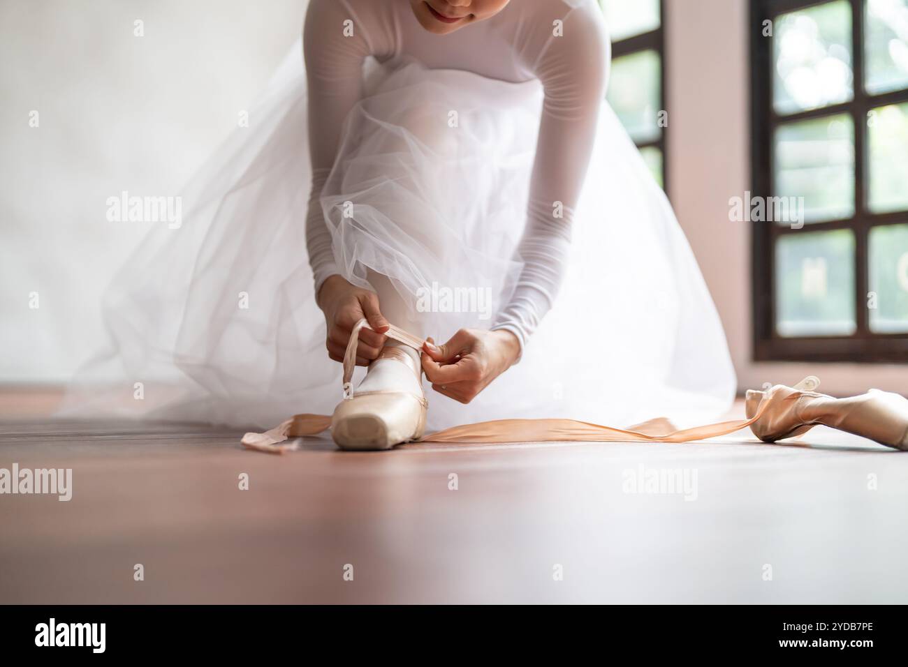 Ballerina in ballet shoes. Asian girlÂ tying ribbons of toe shoes ...