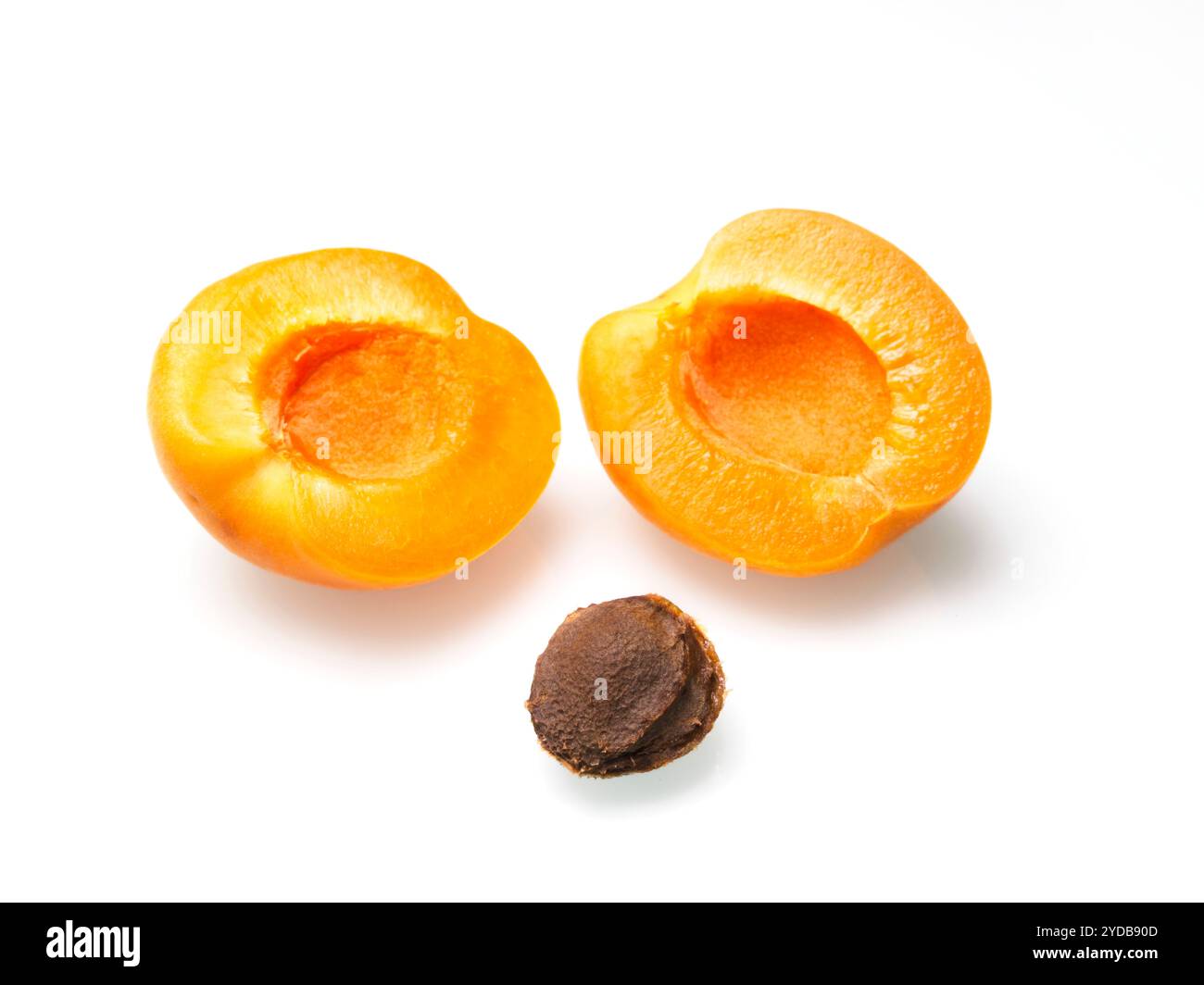 A close up food photo of an apricot cut in half with the pit on a white ...