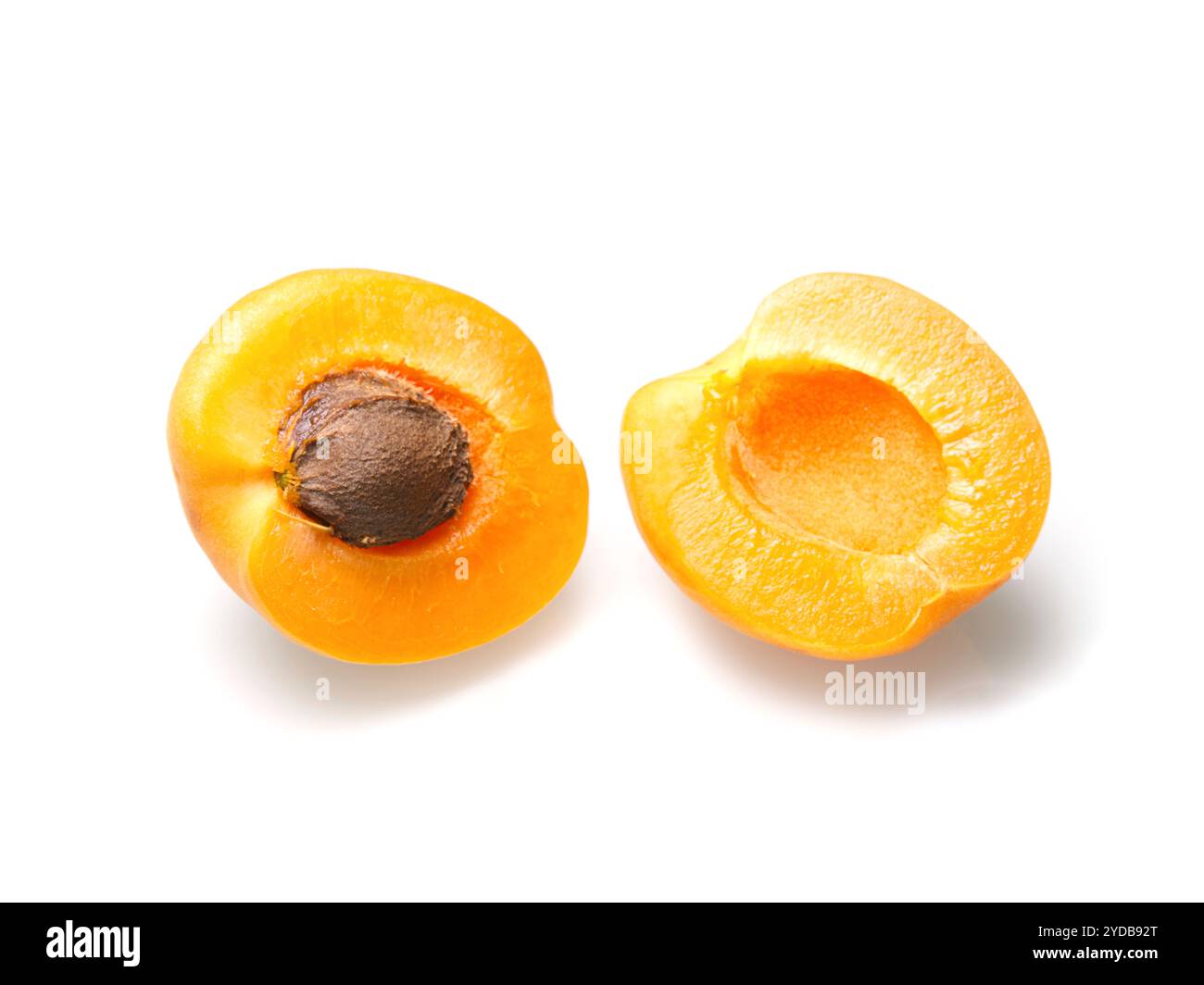 A close up food photo of an apricot cut in half with the pit on a white ...
