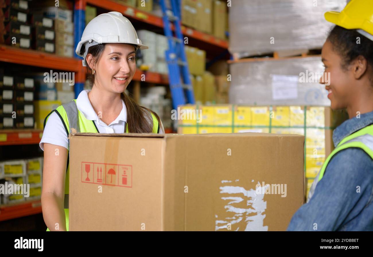 Two girls warehouse workers Help each other lift heavy boxes to move ...