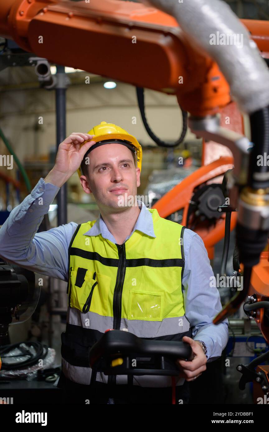 A male worker is controlling a welding robot. by using forcing welding ...