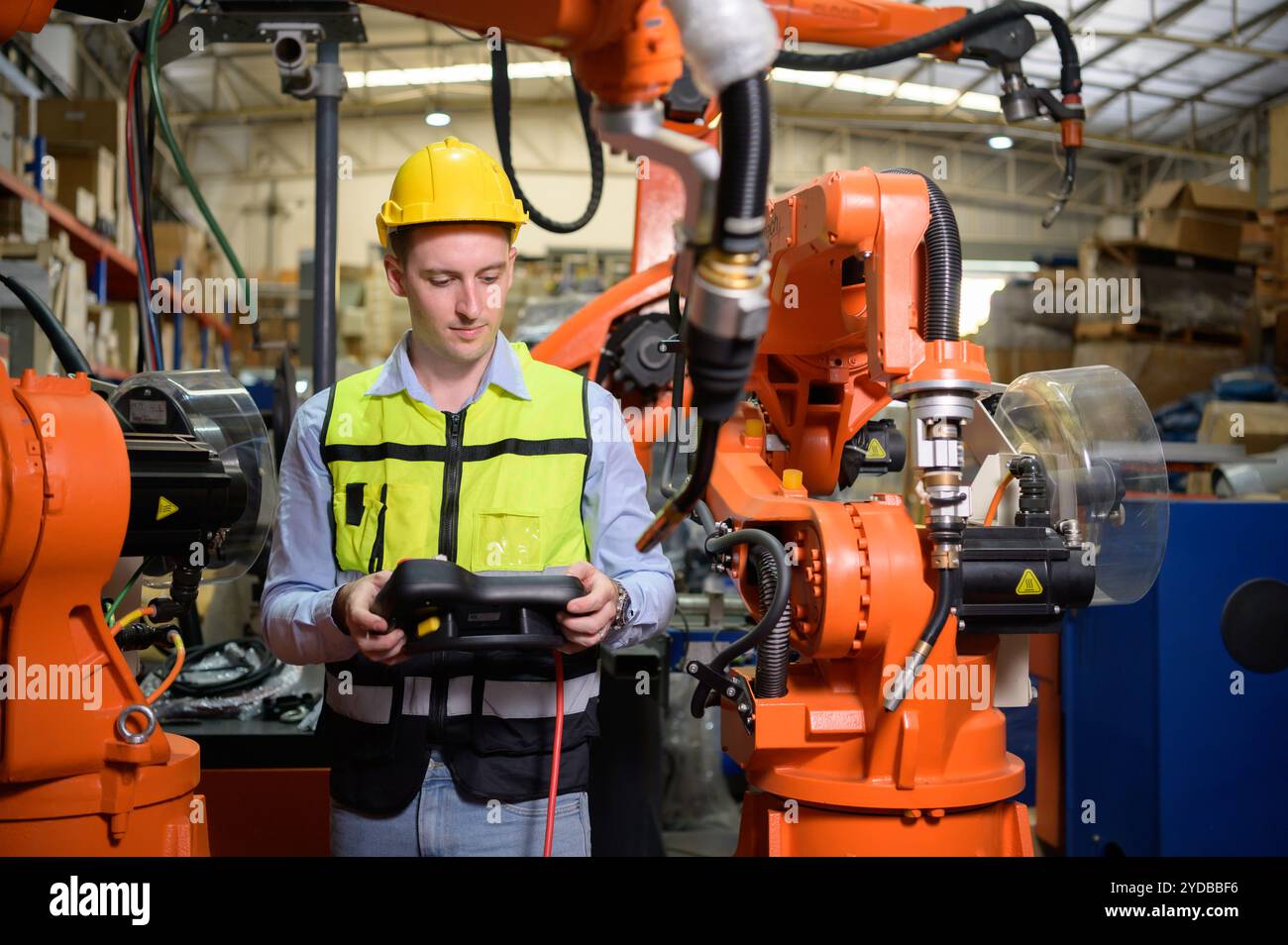 A male worker is controlling a welding robot. by using forcing welding ...