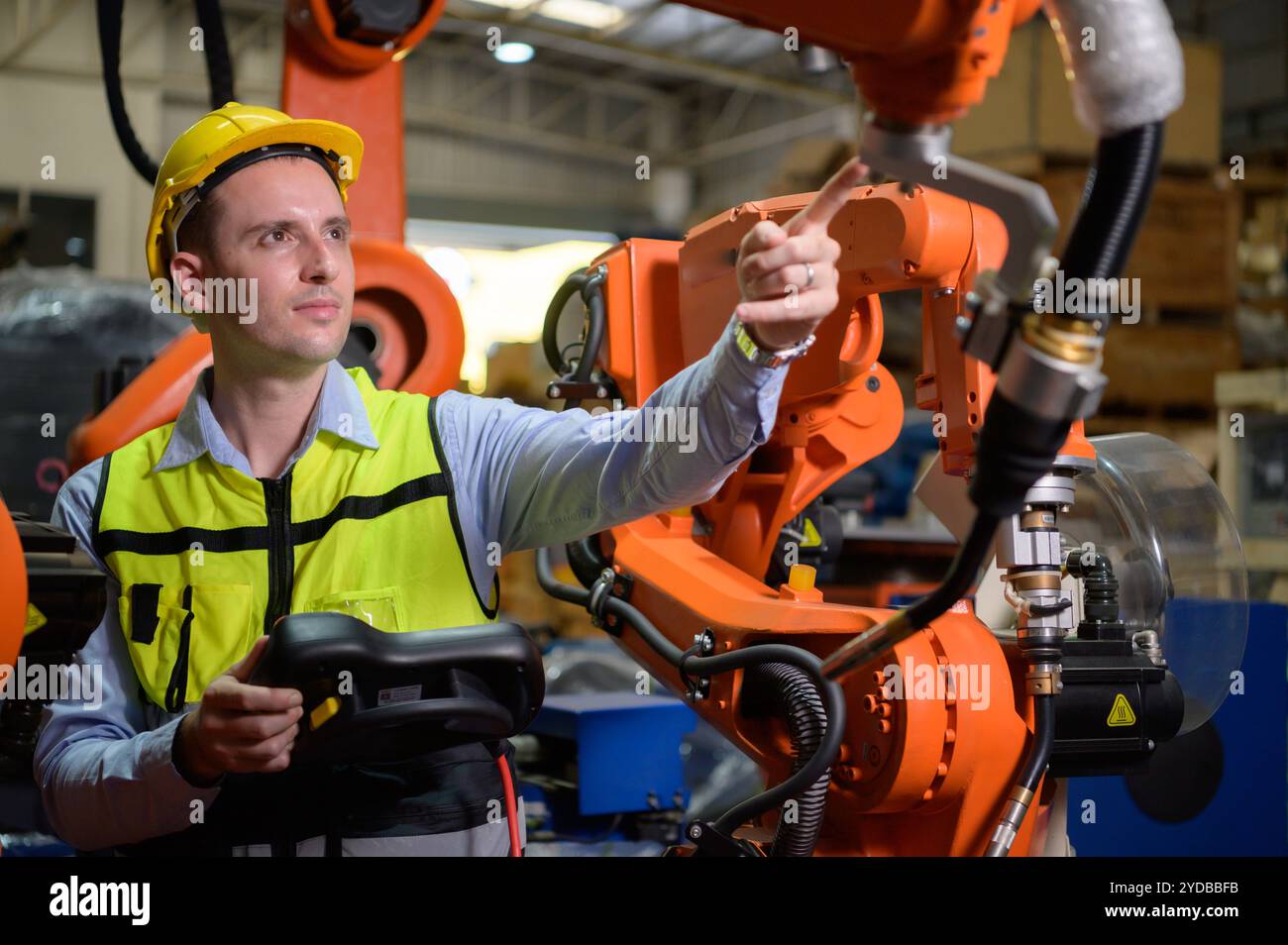 A male worker is controlling a welding robot. by using forcing welding ...