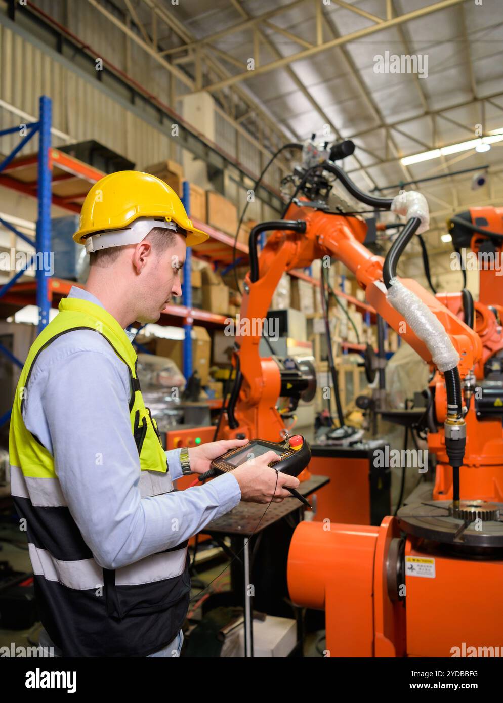 A male worker is controlling a welding robot. by using forcing welding ...