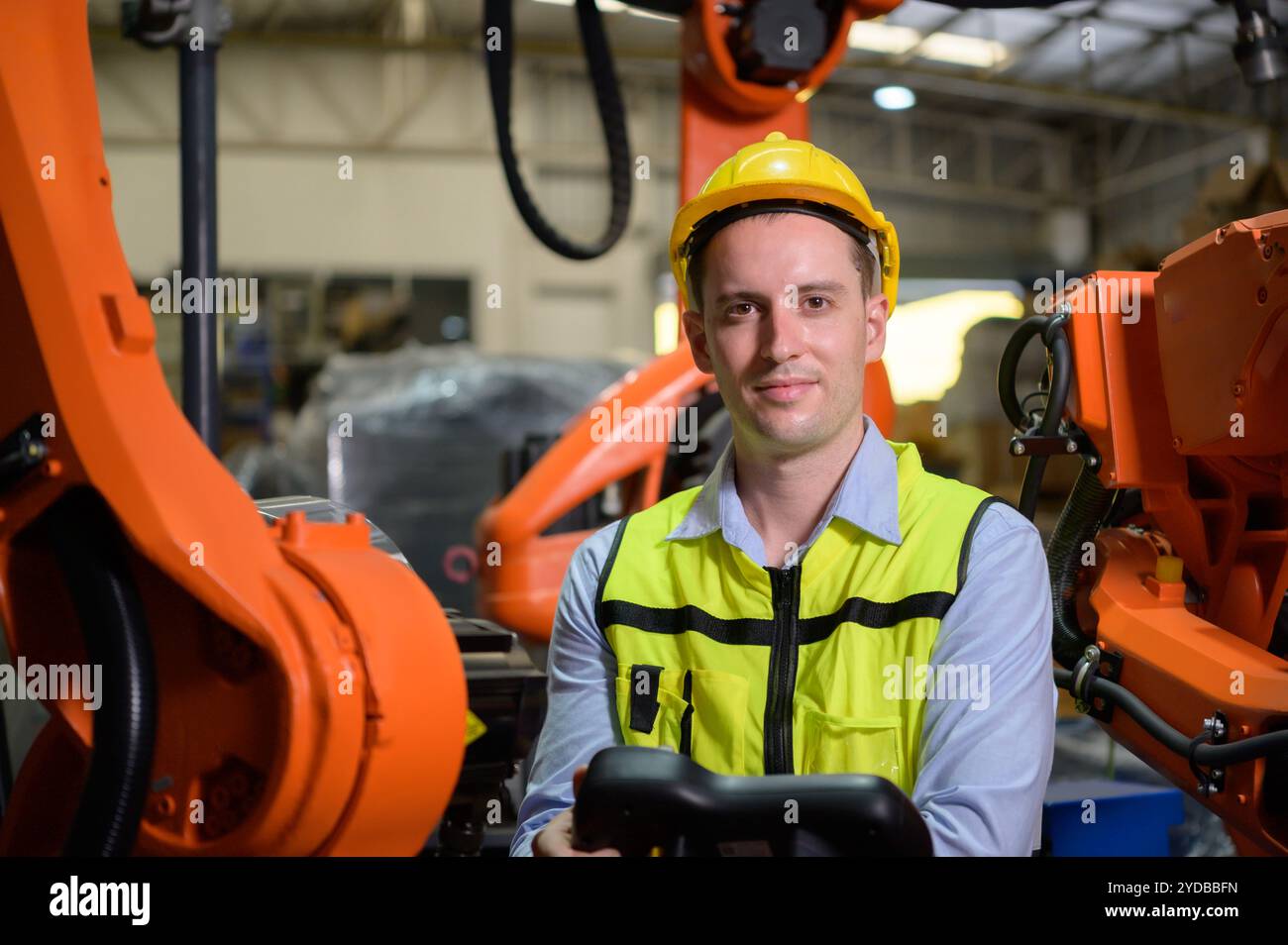 A male worker is controlling a welding robot. by using forcing welding ...