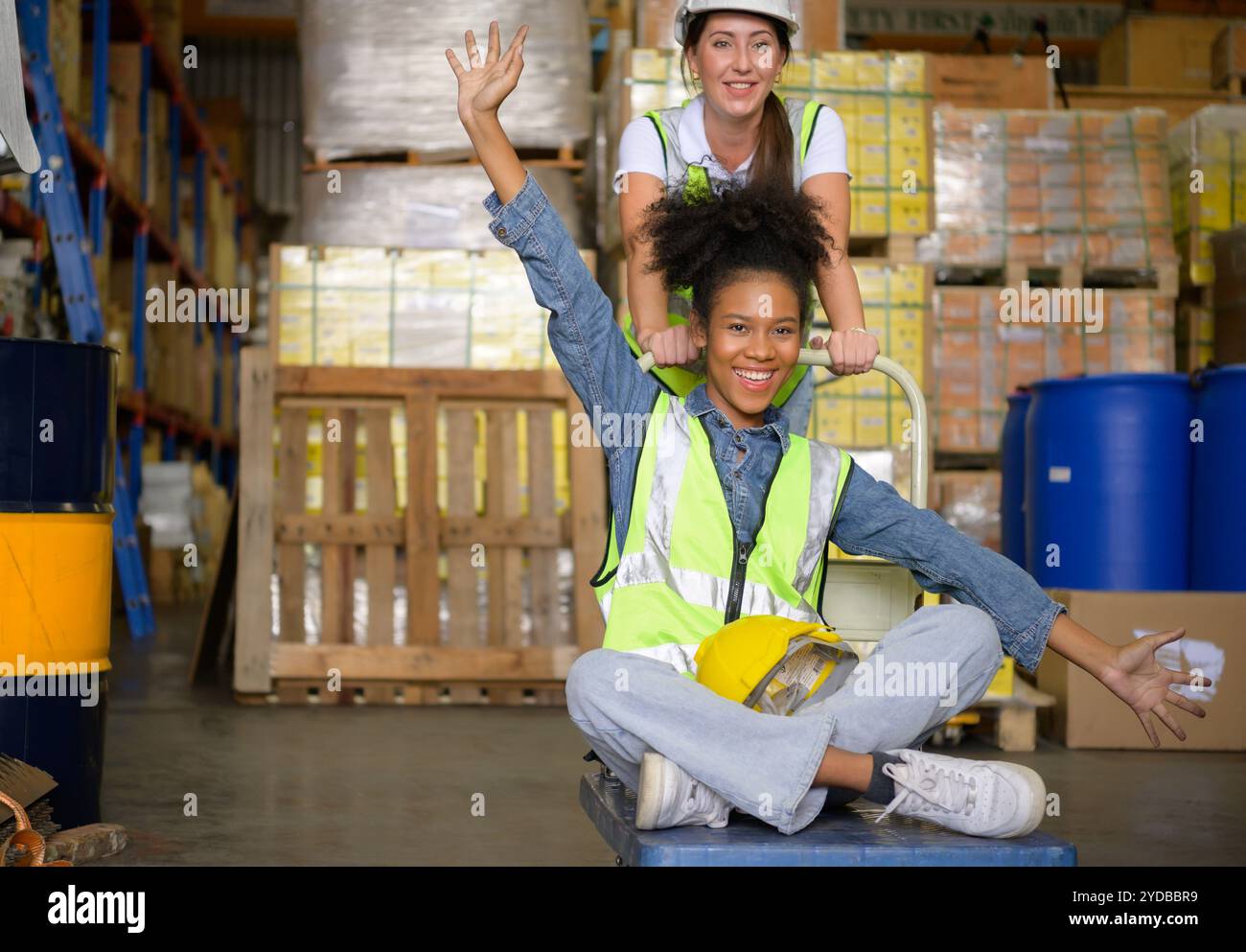 Two girls warehouse workers relax and play during the break of the day ...
