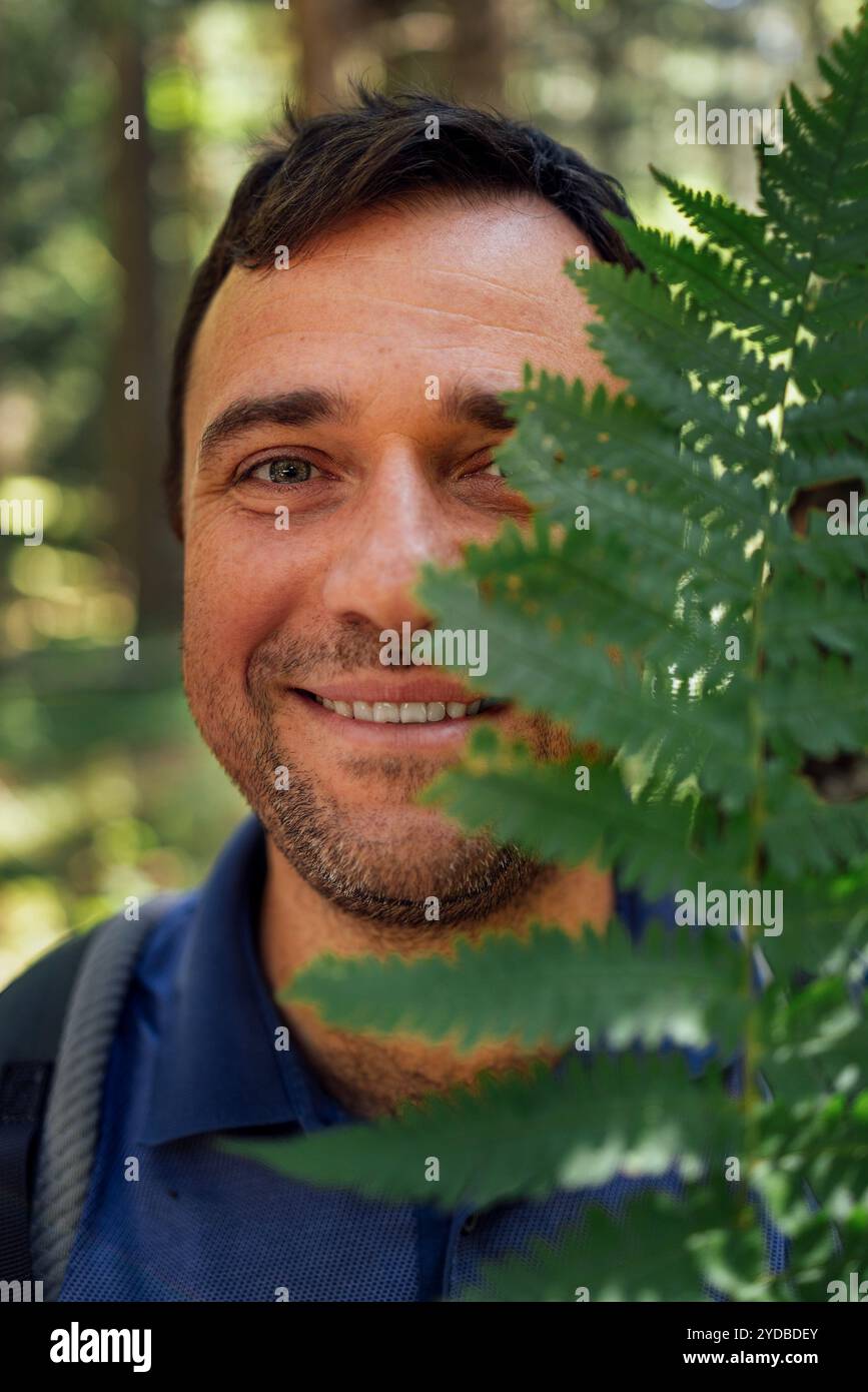 Close-up portrait of young happy man with fern in nature. Smiling ...