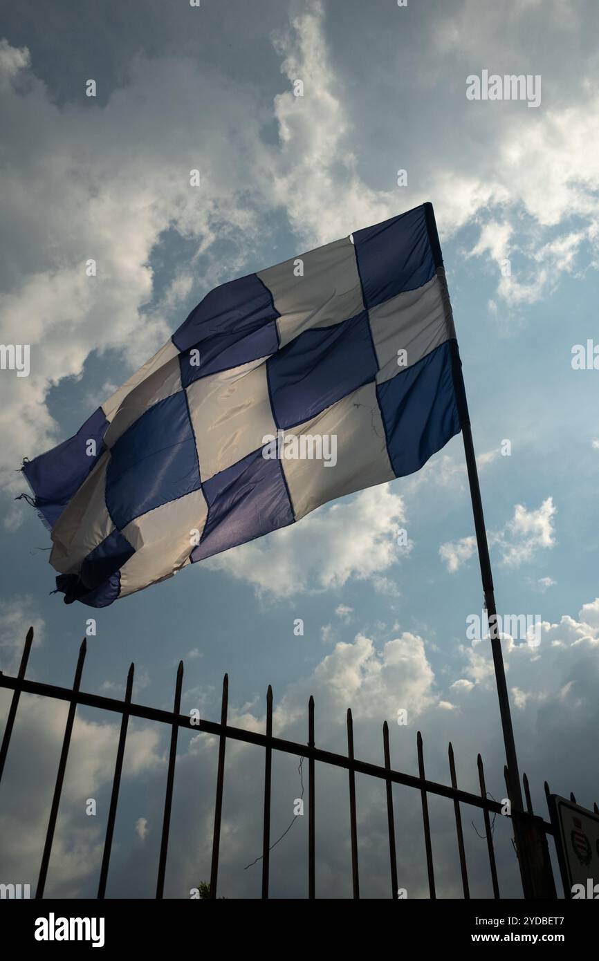 Blue and white checkered flag in the wind with clouds in background ...